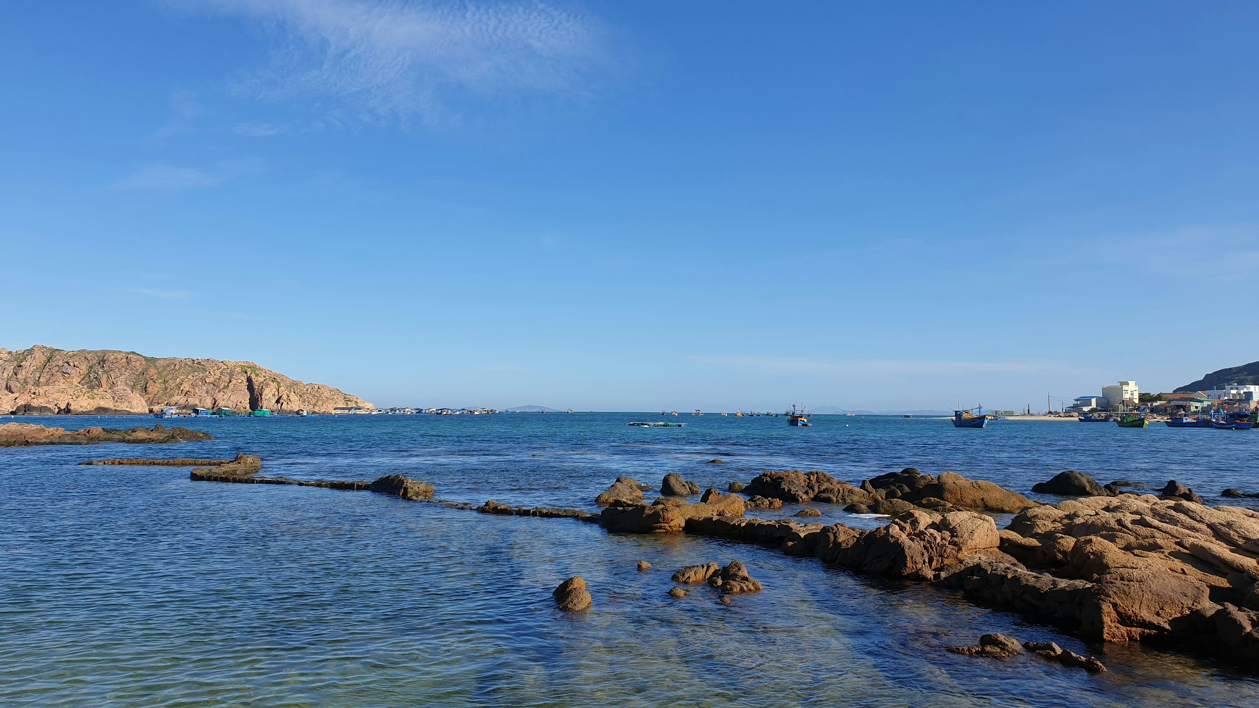 Rocky shoreline meeting the calm blue sea under a cloudless sky.