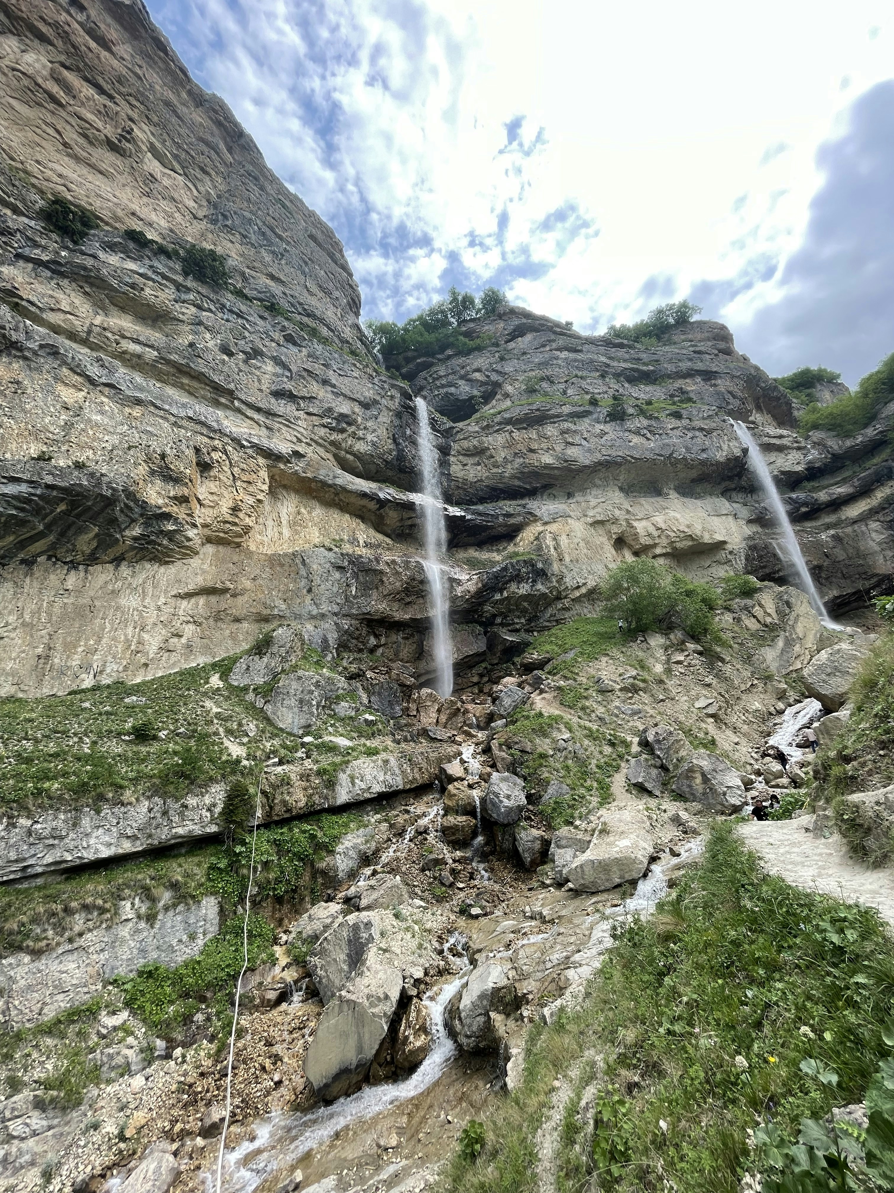 Twin cascades carve a limestone canyon under a bright sky