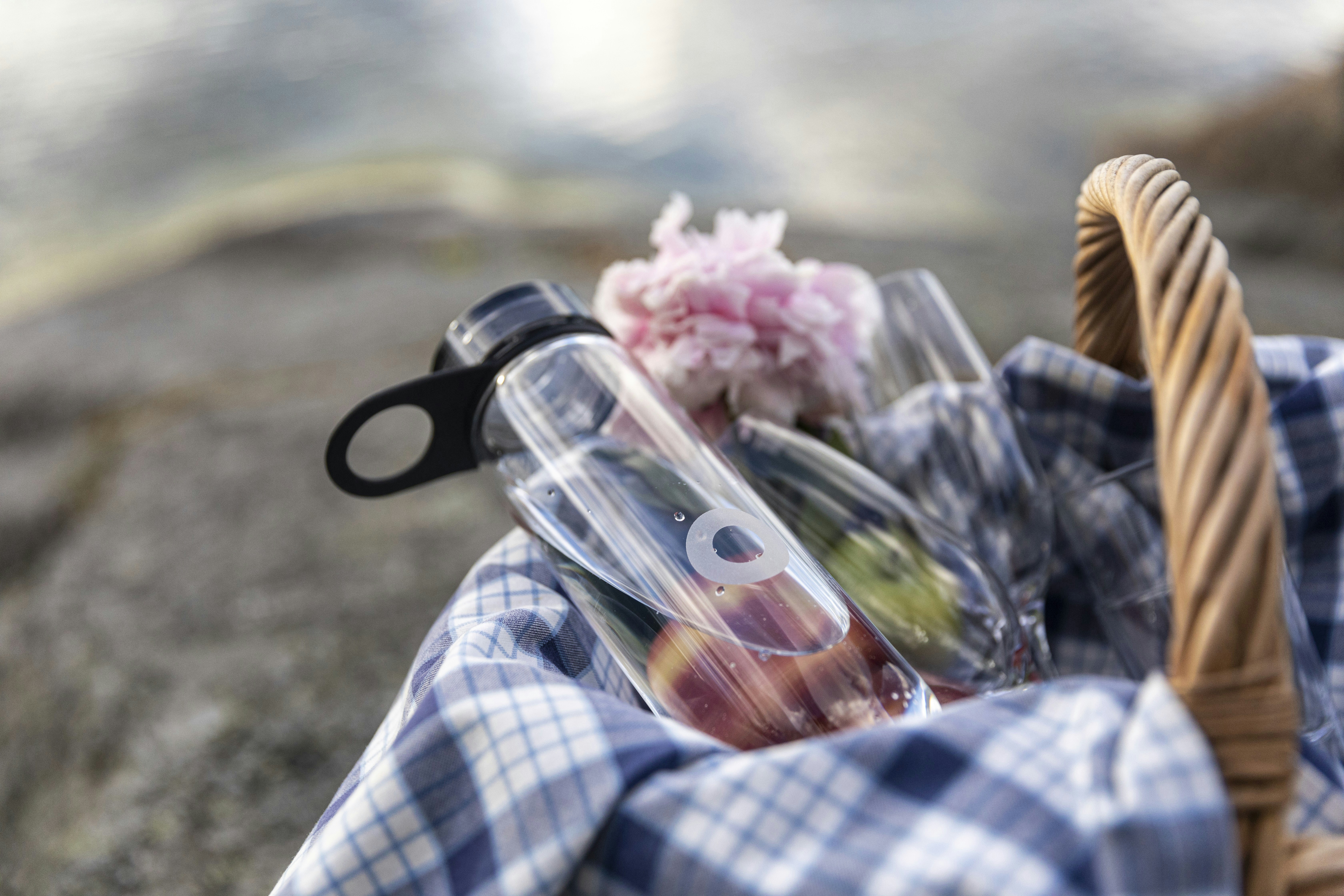 Seaside Picnic in Focus: A Glass Bottle, Pink Blooms, and a Woven Basket