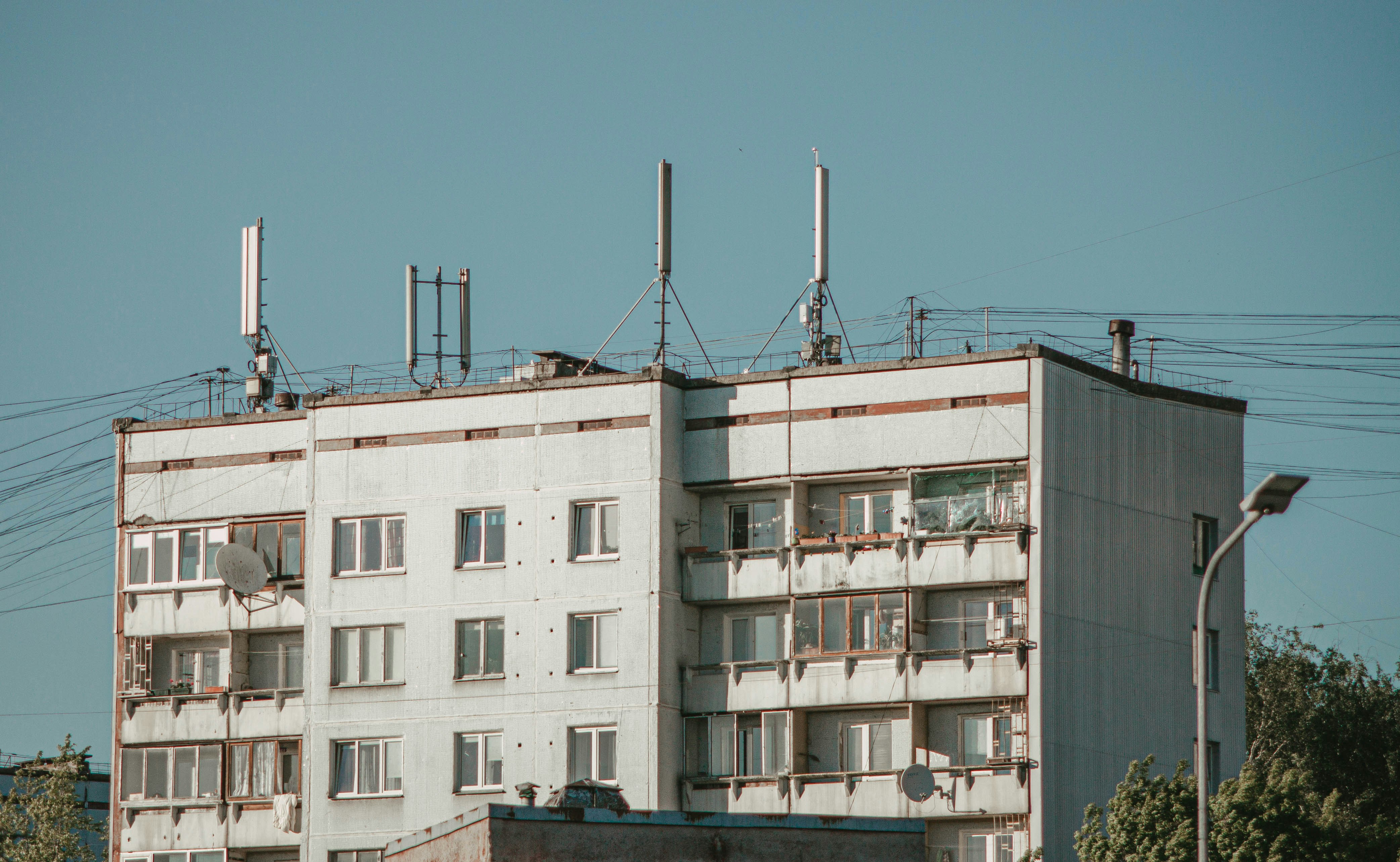 Apartment building with rooftop antennas under a clear blue sky.