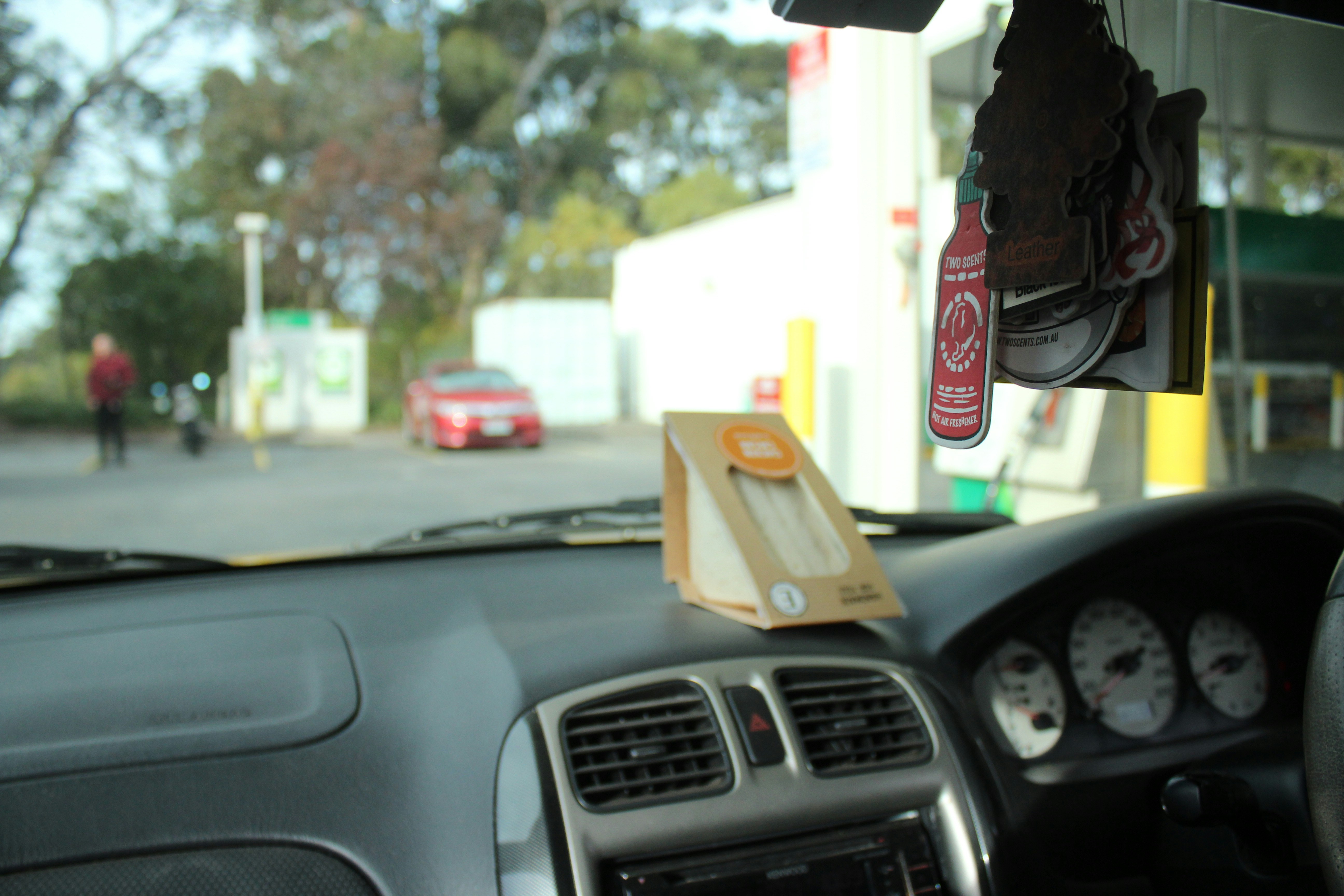 Beige Cardboard Tag Balancing on the Dash, Framing a Gas-Station View