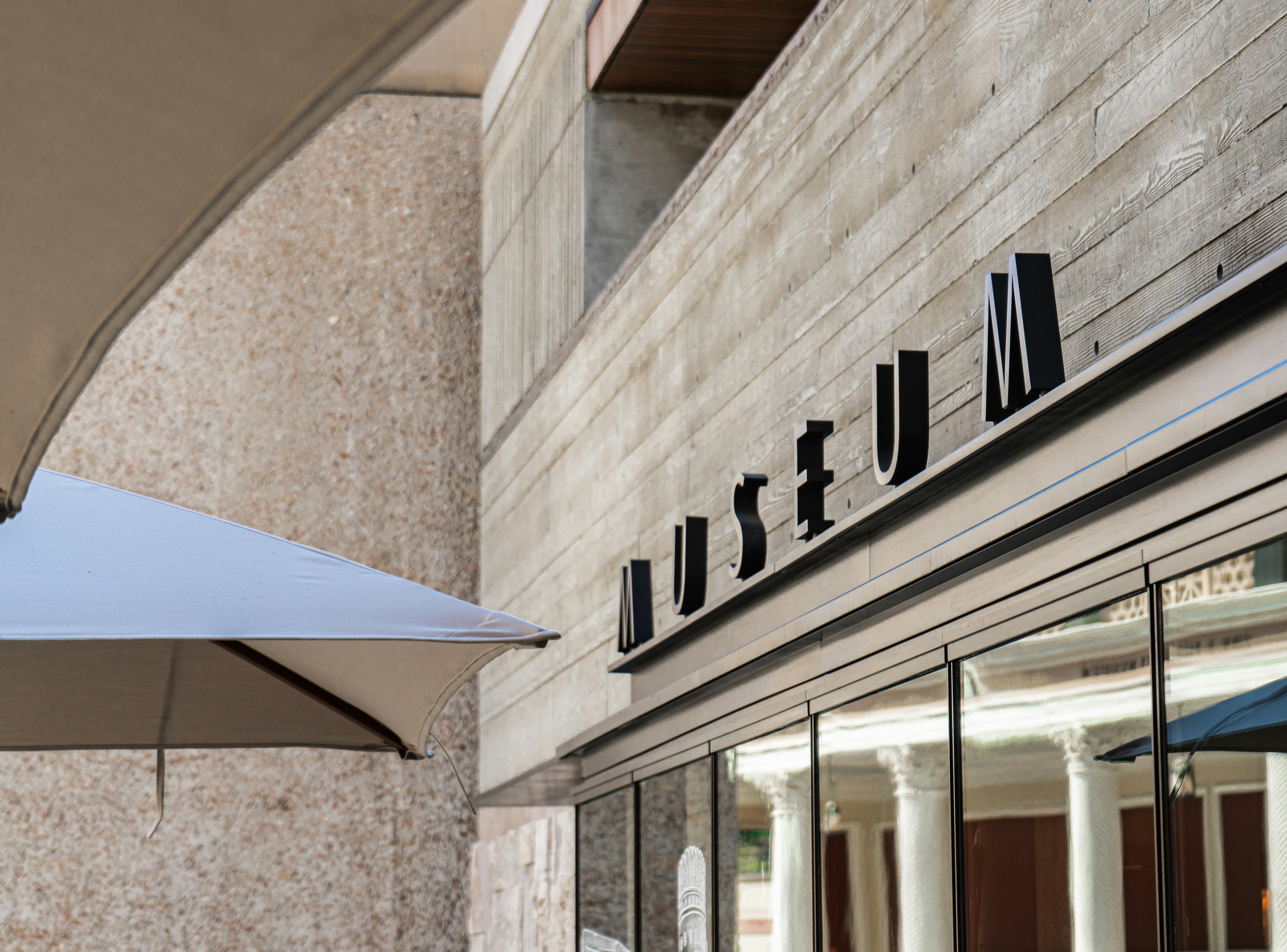 An umbrella is outside of a building with a sign on it photo – Free ...