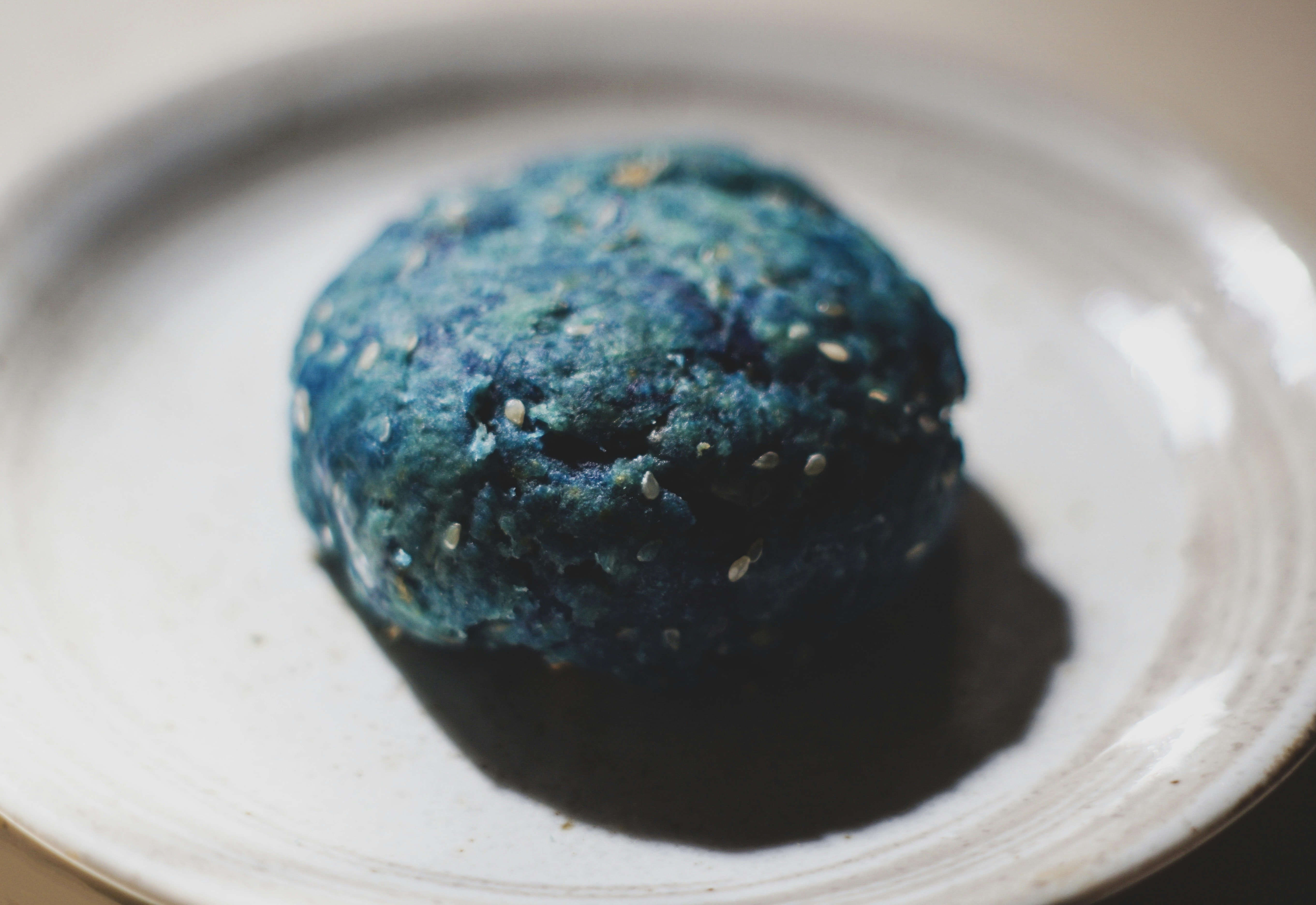 Azure Crunch on White: a textured blue sesame confection under soft plate light