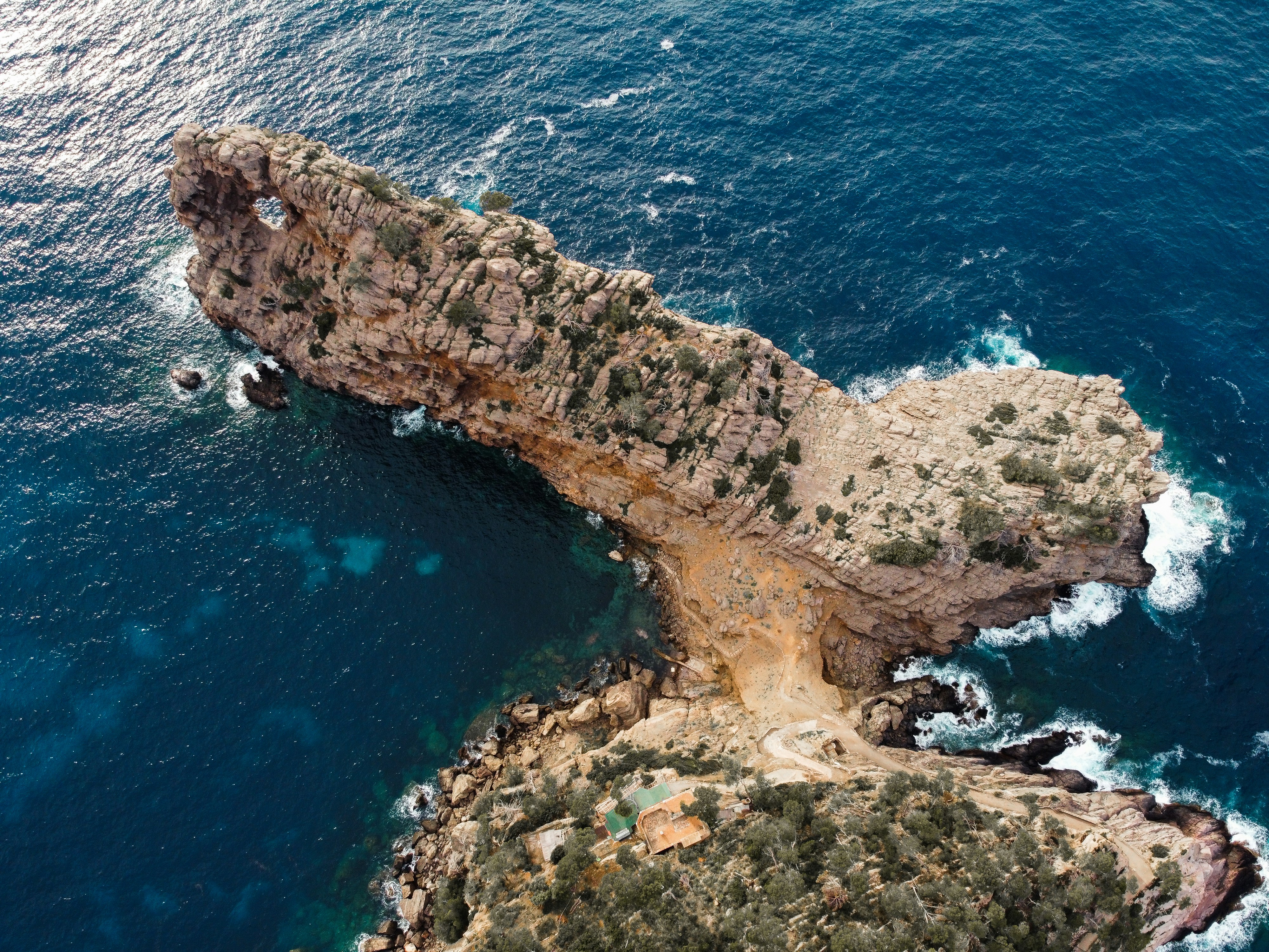 Aerial view of a rugged peninsula surrounded by deep blue ocean waves.
