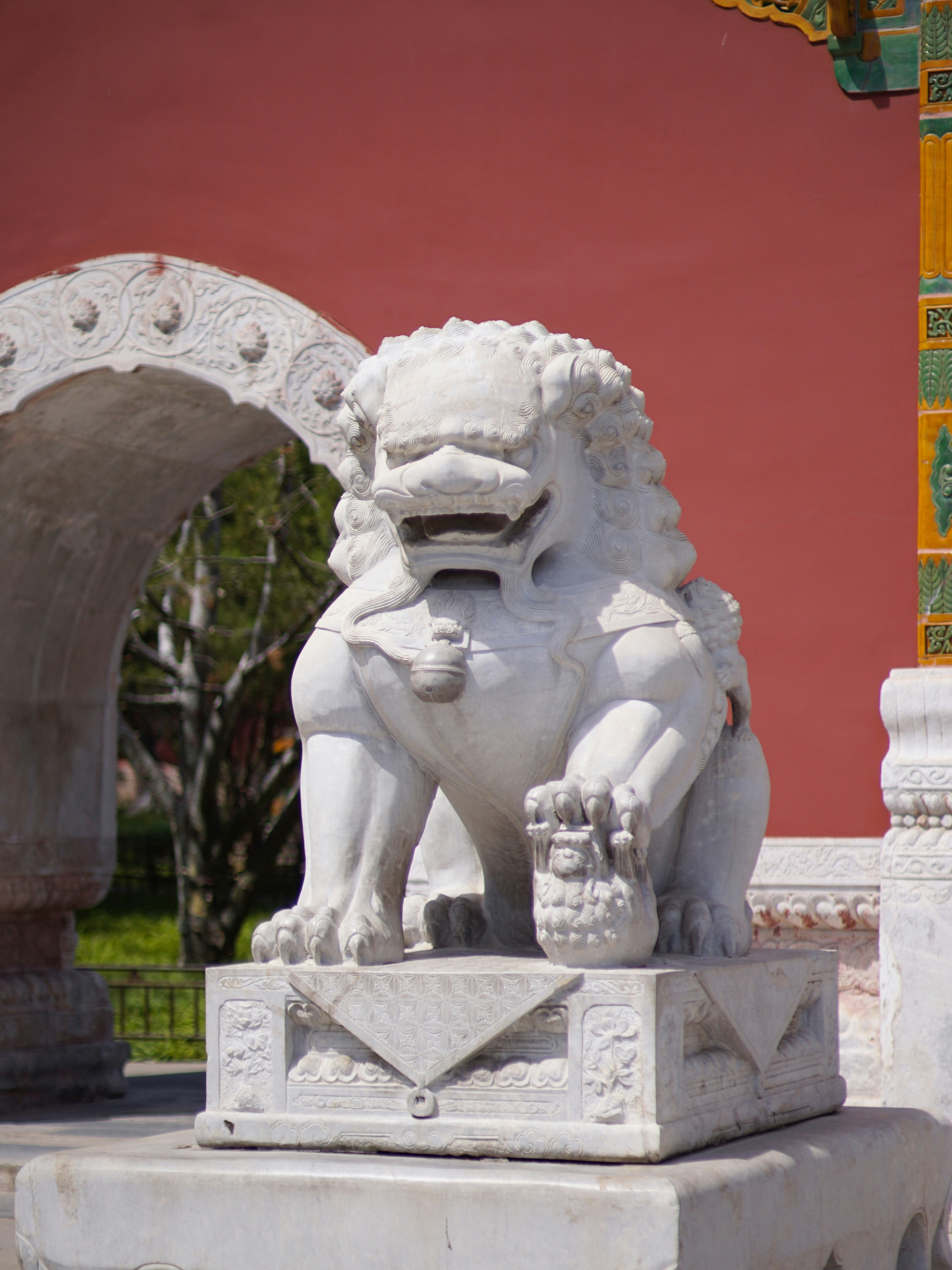 Intricately carved white lion statue stands sentinel at an ornate entrance, embodying traditional architectural elegance.