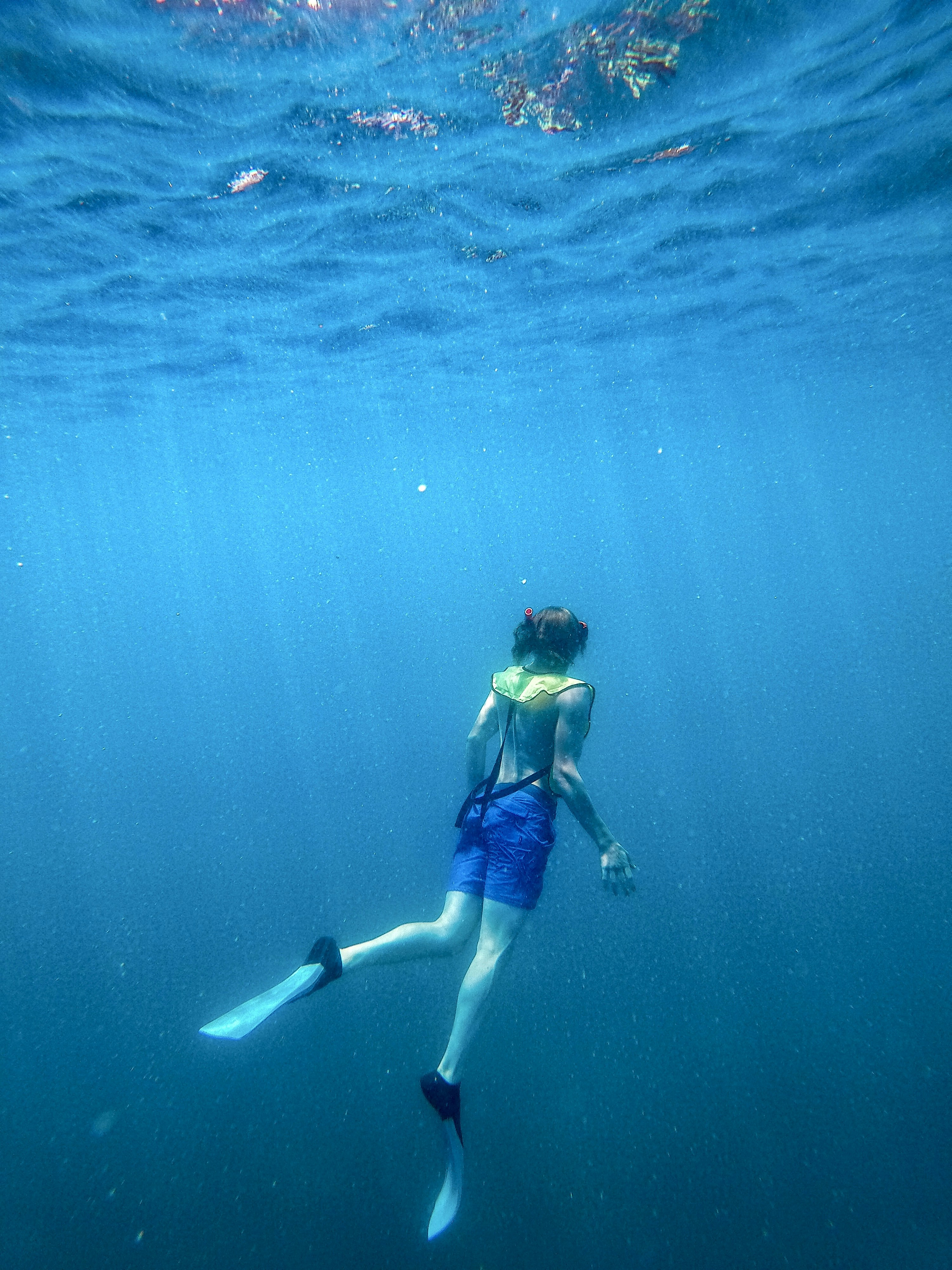 A snorkeler glides gracefully underwater, surrounded by vibrant blue hues and sunlit ripples above. The scene captures the tranquility of ocean exploration.