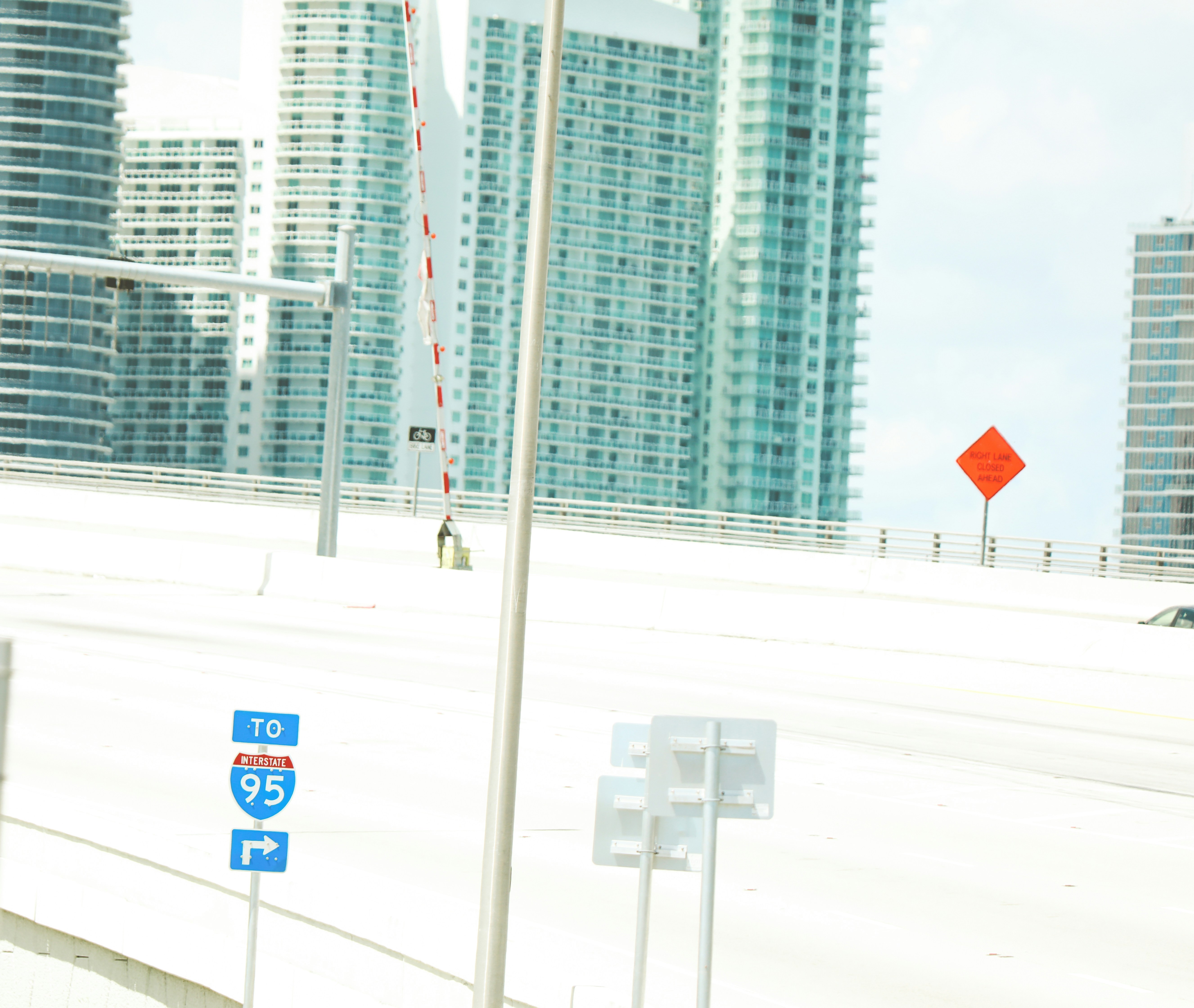 Highway signs directing traffic towards Interstate 95, framed by modern skyscrapers in a bustling urban environment.
