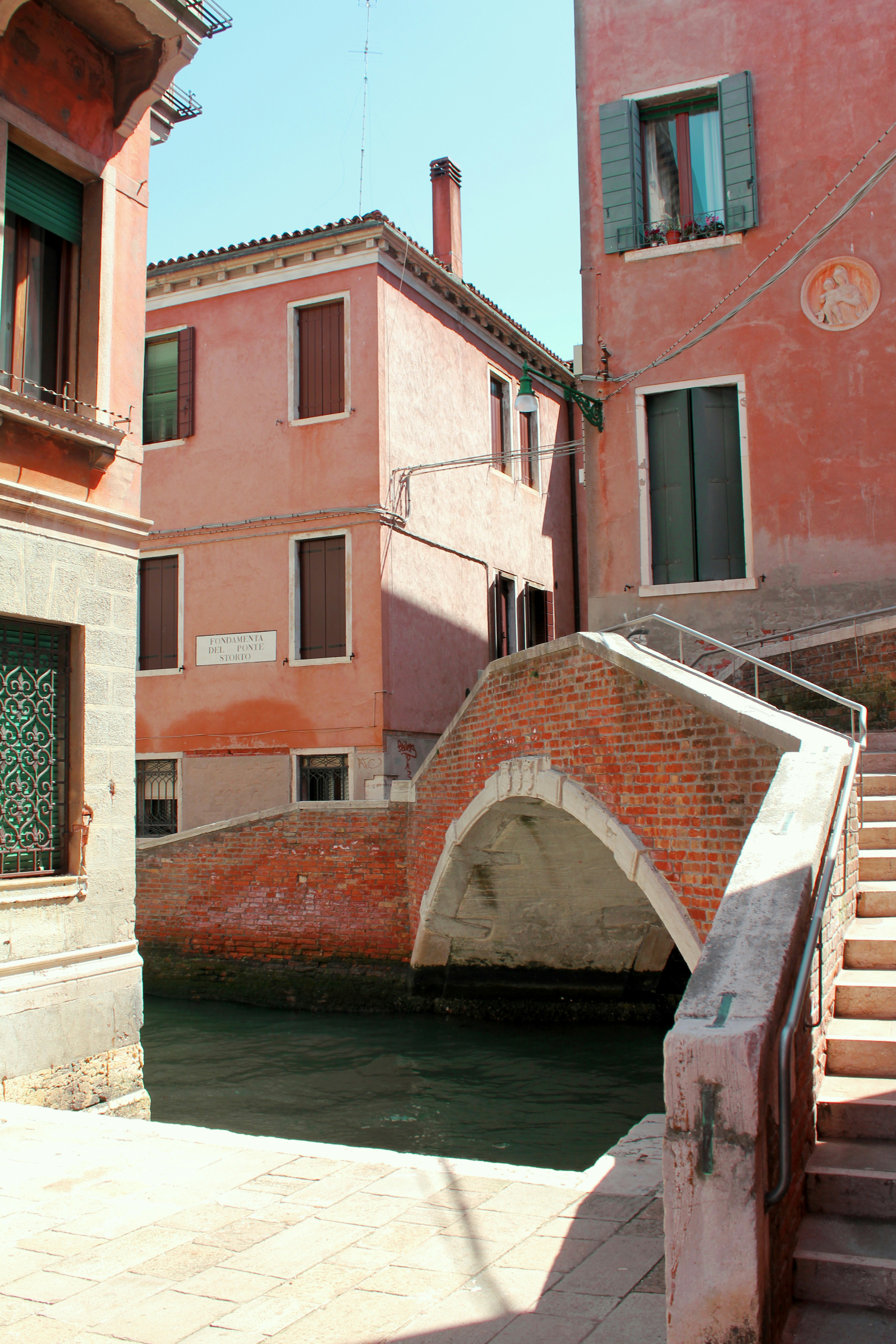Brick-arched Canal Bridge Framed by Coral-Pink Facades