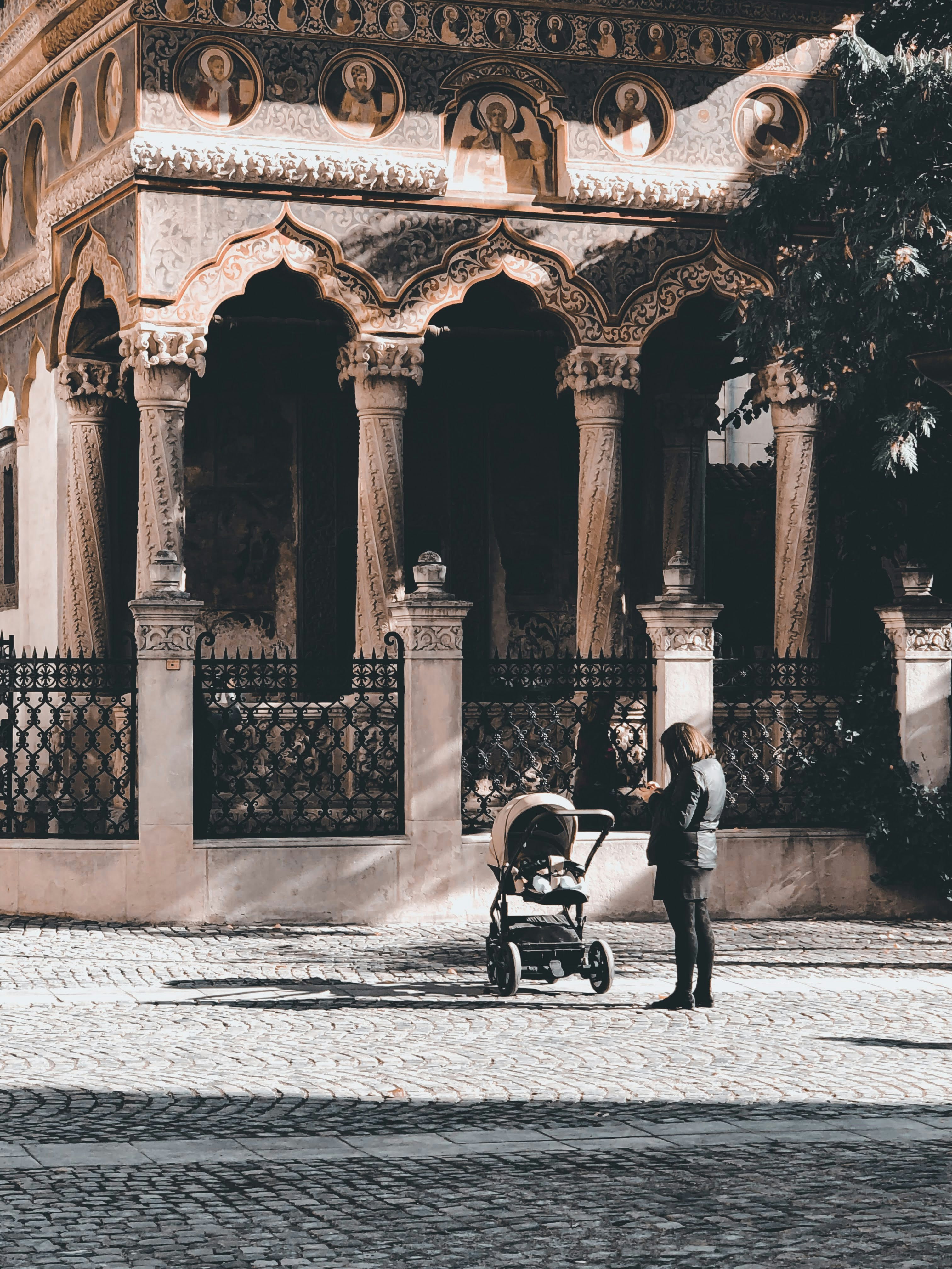 Stone Arcade Reverie: A Mother and Pram Beneath Ornate Arches