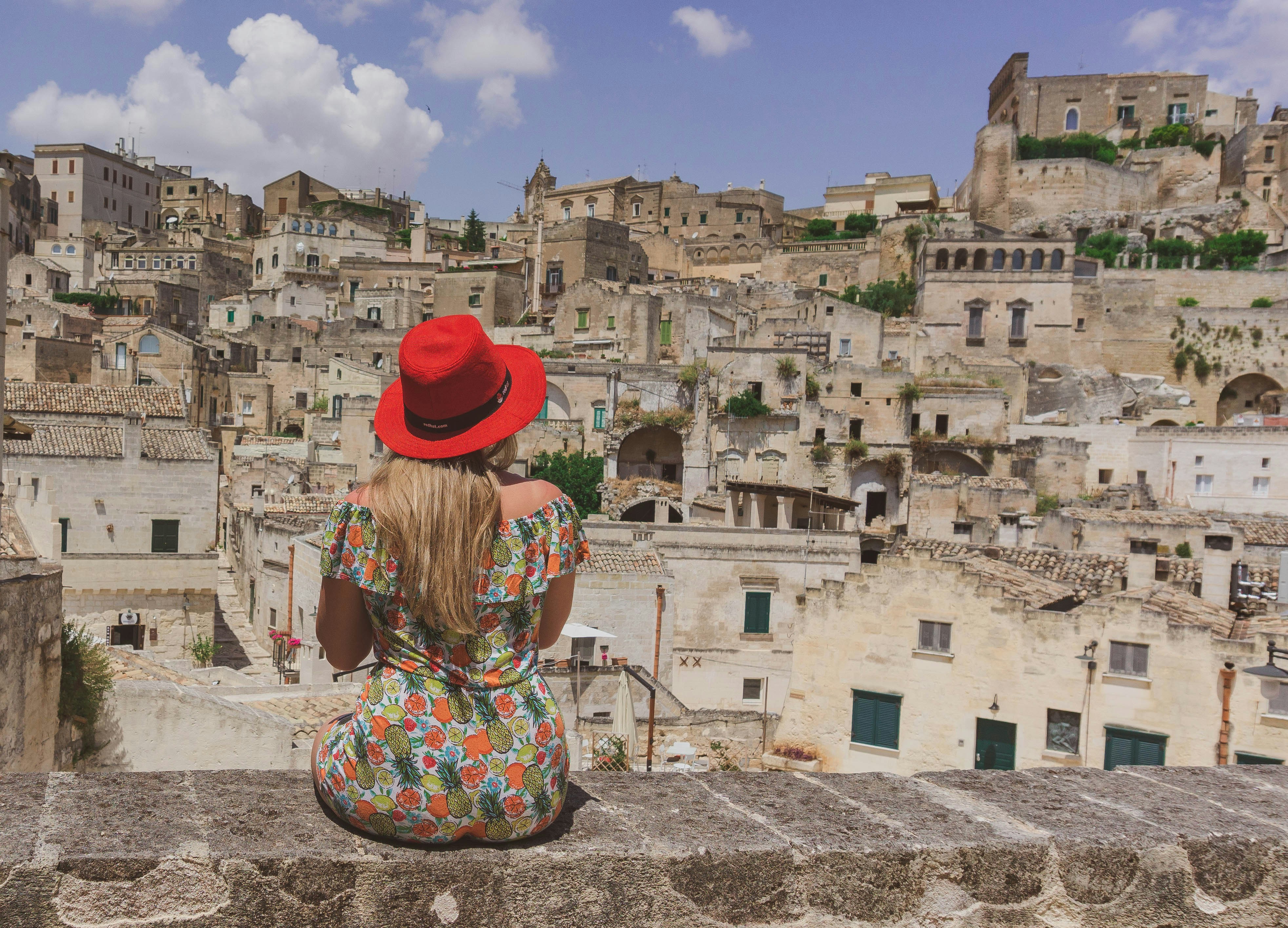 Matera city, Italy, Puglia Region | woman in red hat standing on gray concrete pavement during daytime