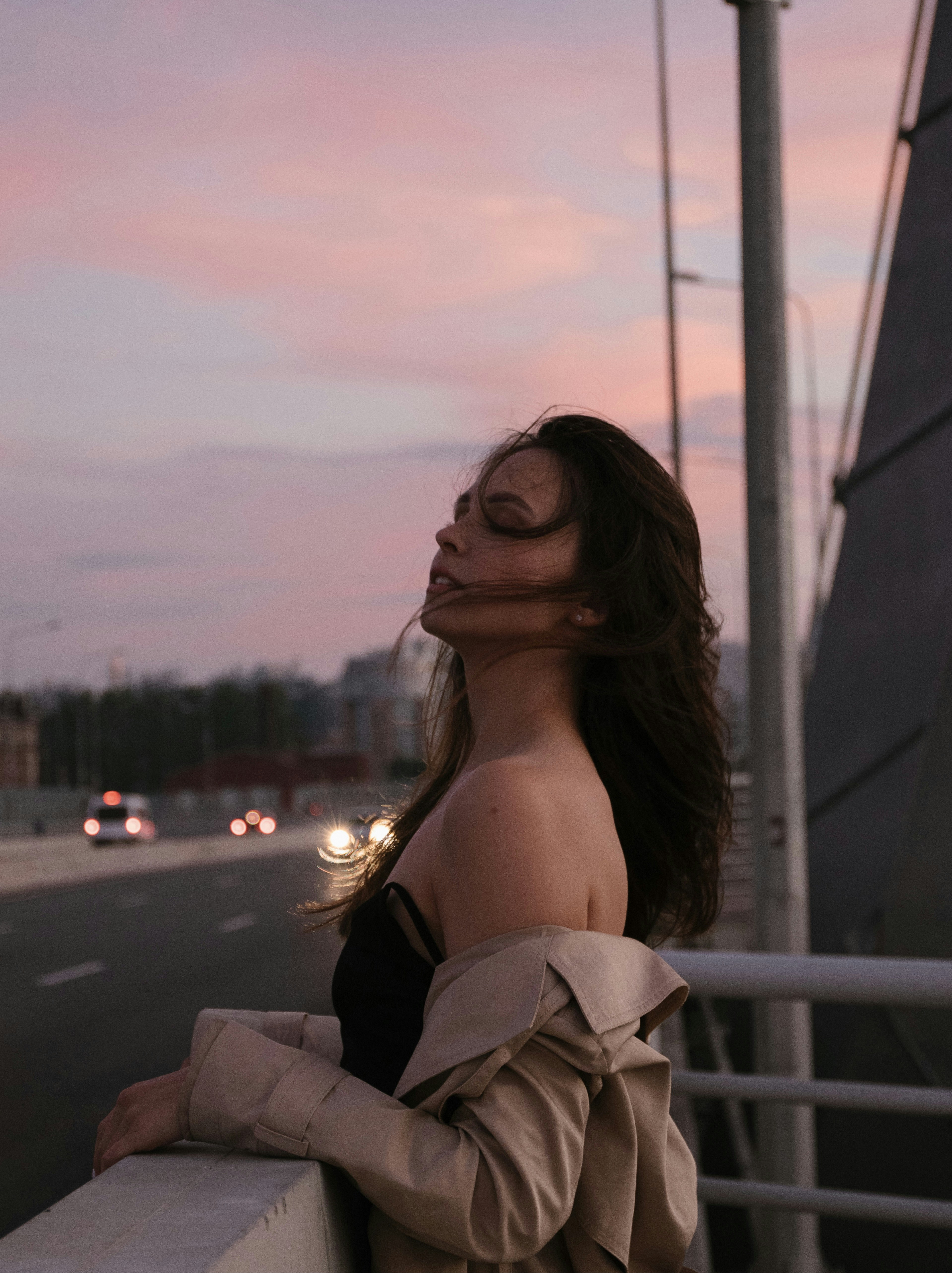 woman in brown coat wearing eyeglasses standing on road during daytime