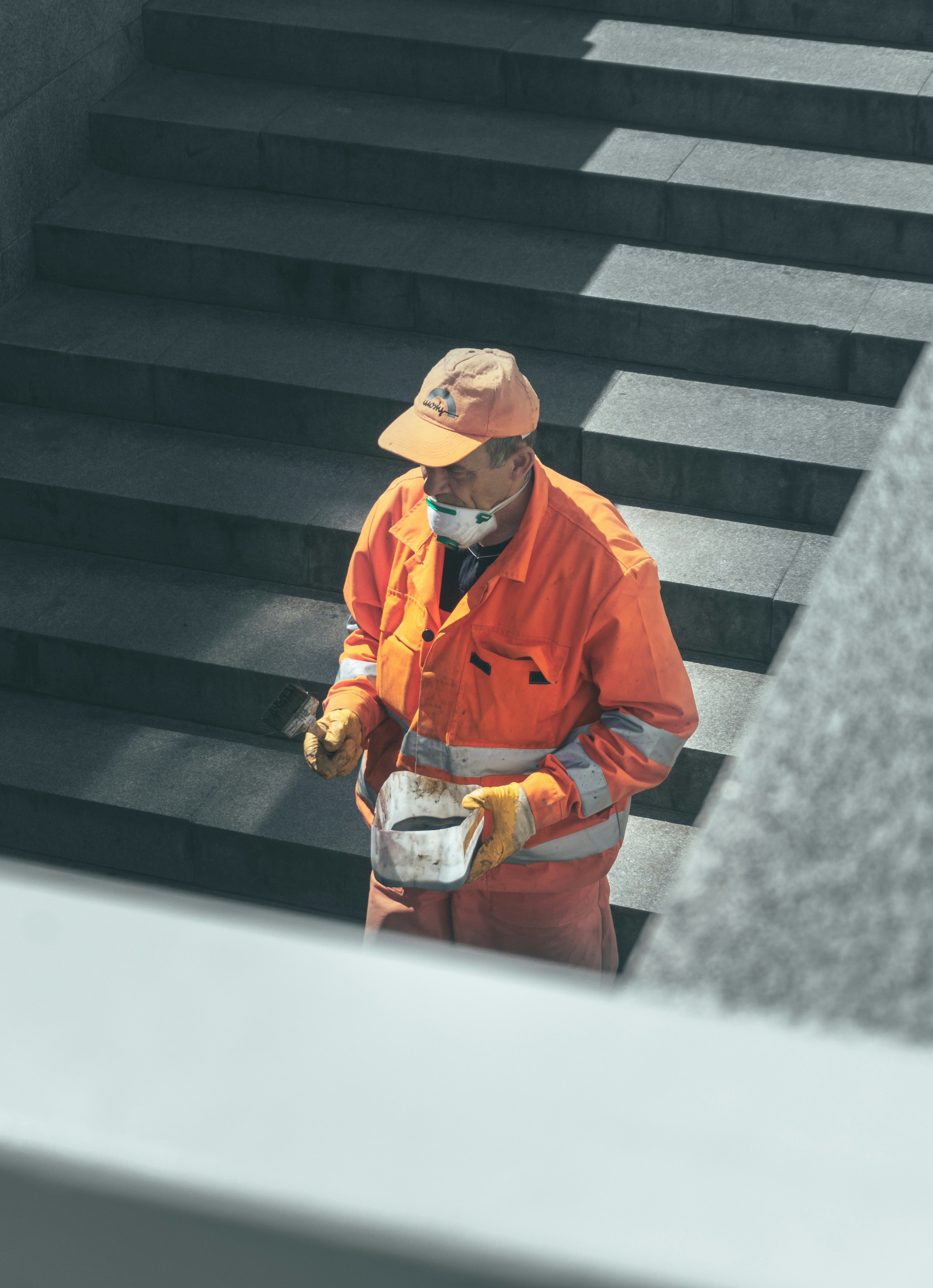 Orange-Suited Worker on Sunlit Concrete Stairs