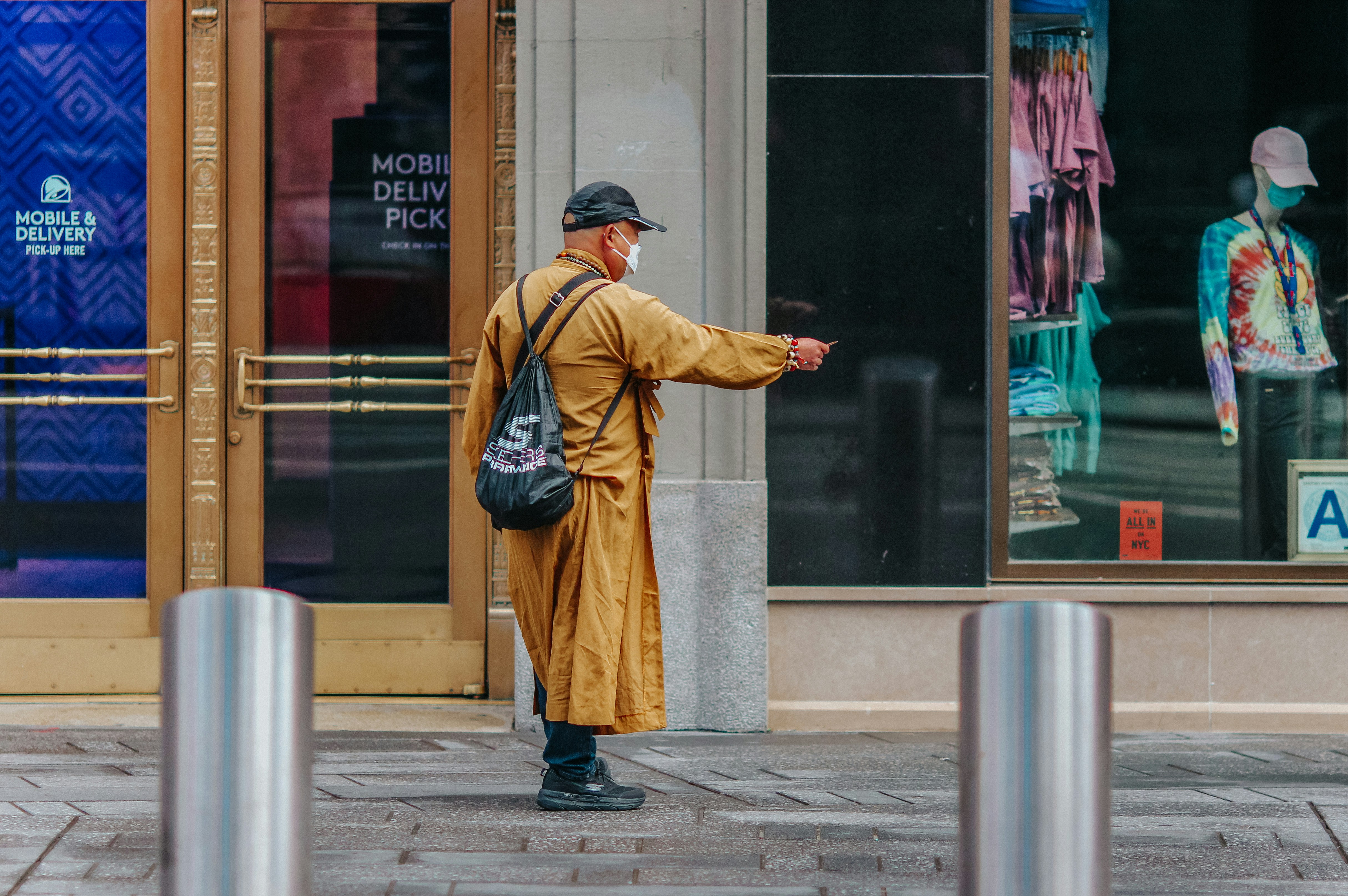 Man in brown coat and black cap walking on sidewalk during daytime ...