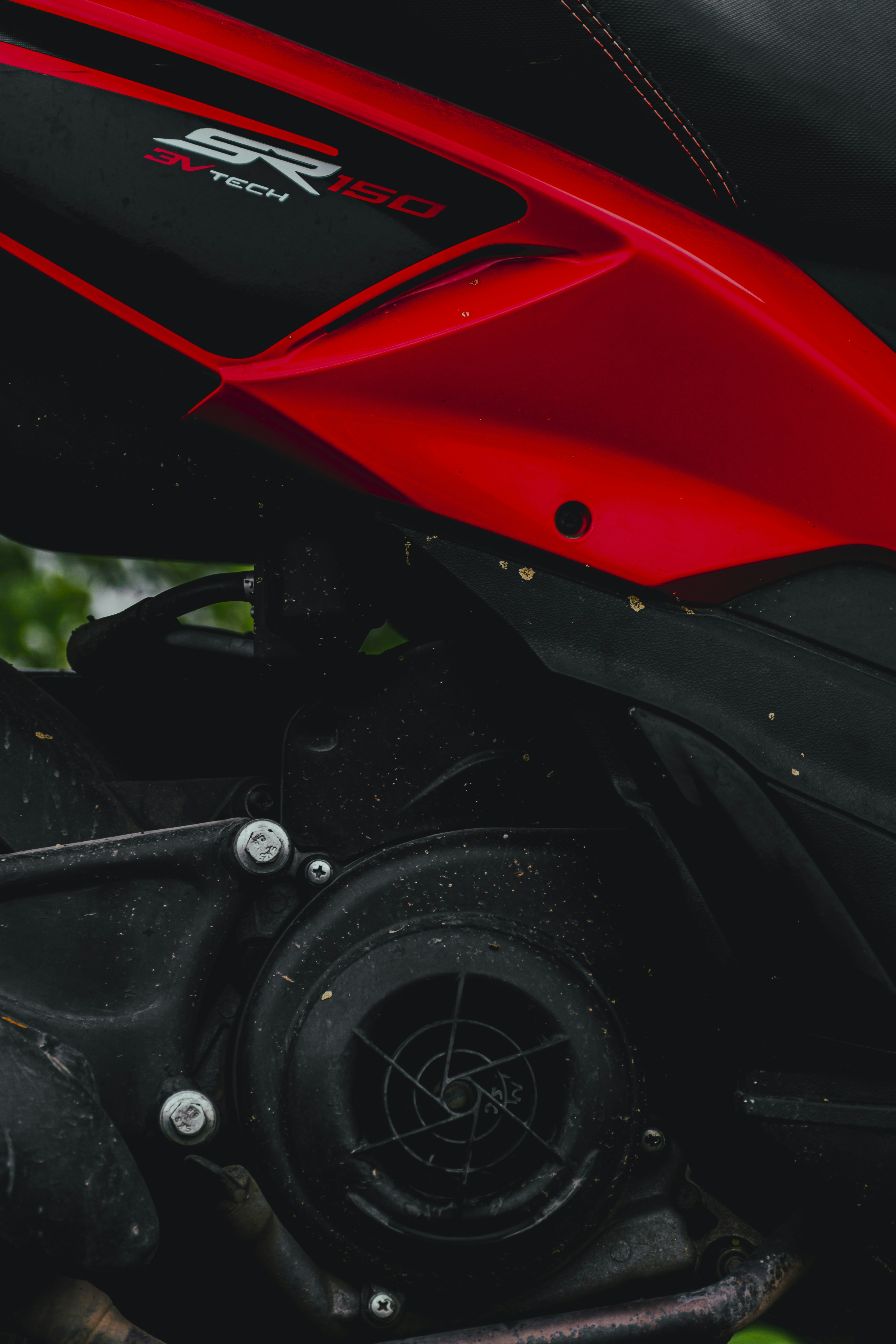 Close-up of a motorcycle's engine compartment showcasing intricate details and vibrant red accents. The focus is on the SR 150 branding and mechanical components.