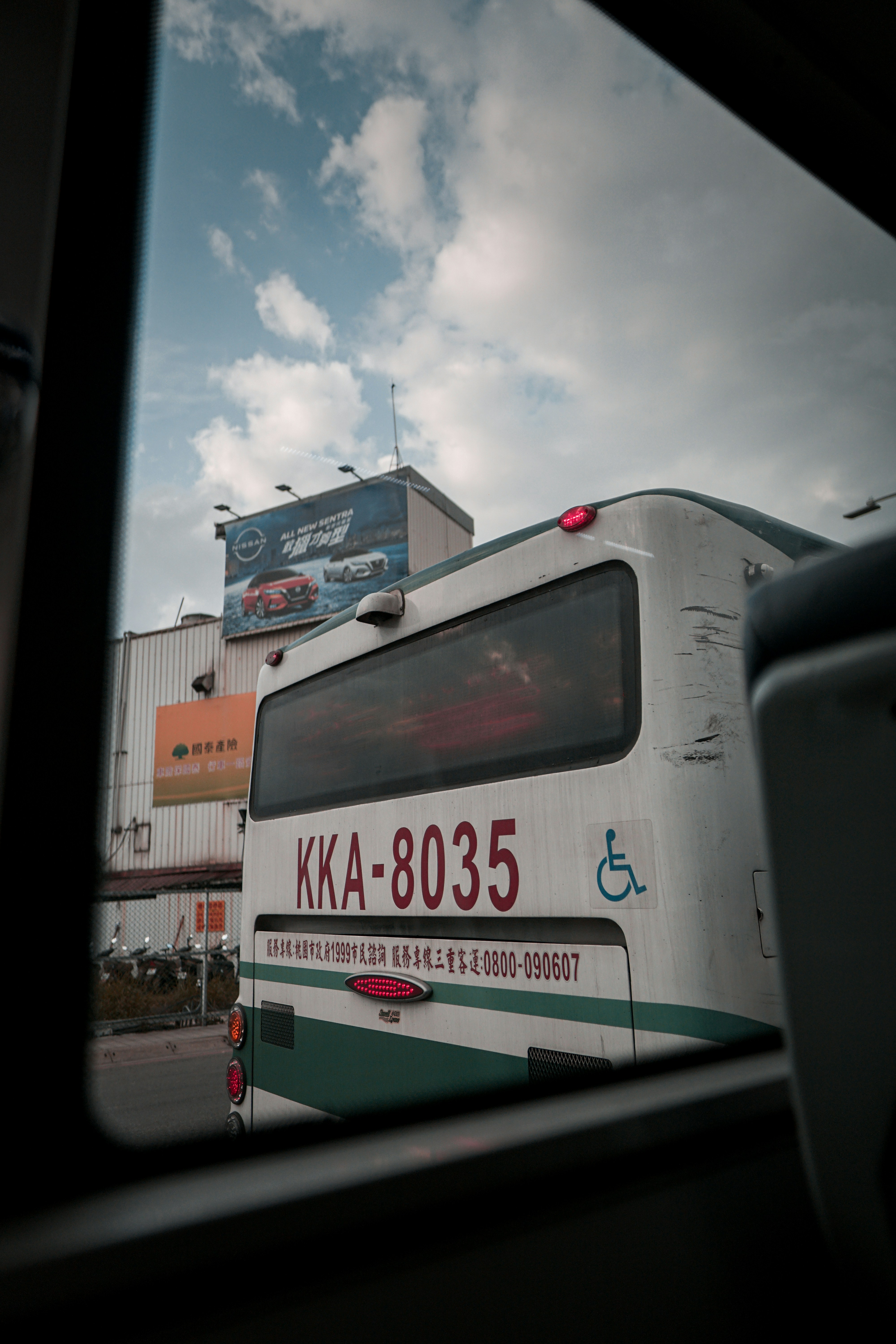 Tail-Light Portrait: Bus Framed by a Car Window