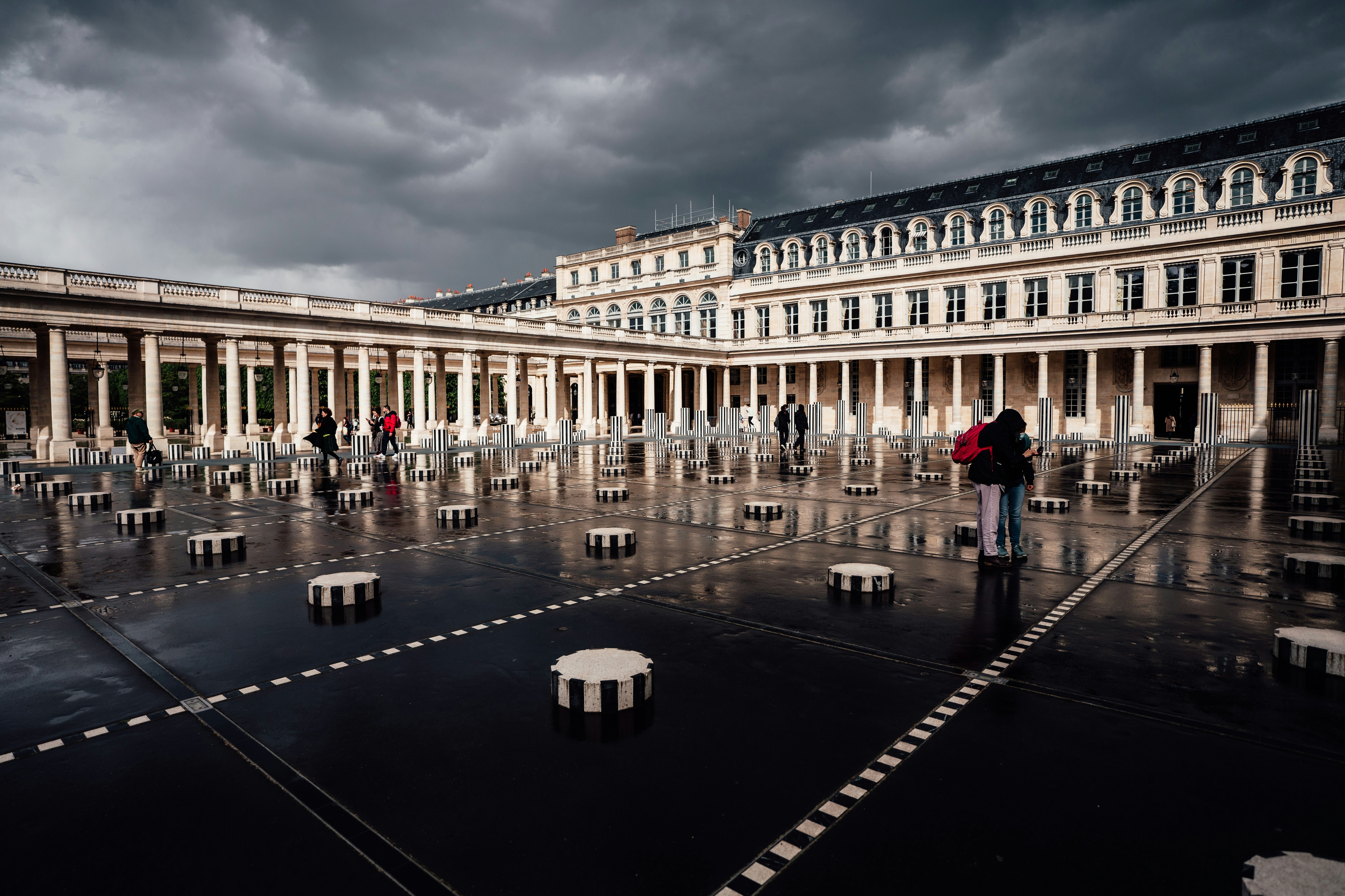 Monumental Courtyard Echoes: Rain-Slicked Mosaic and Lone Visitors