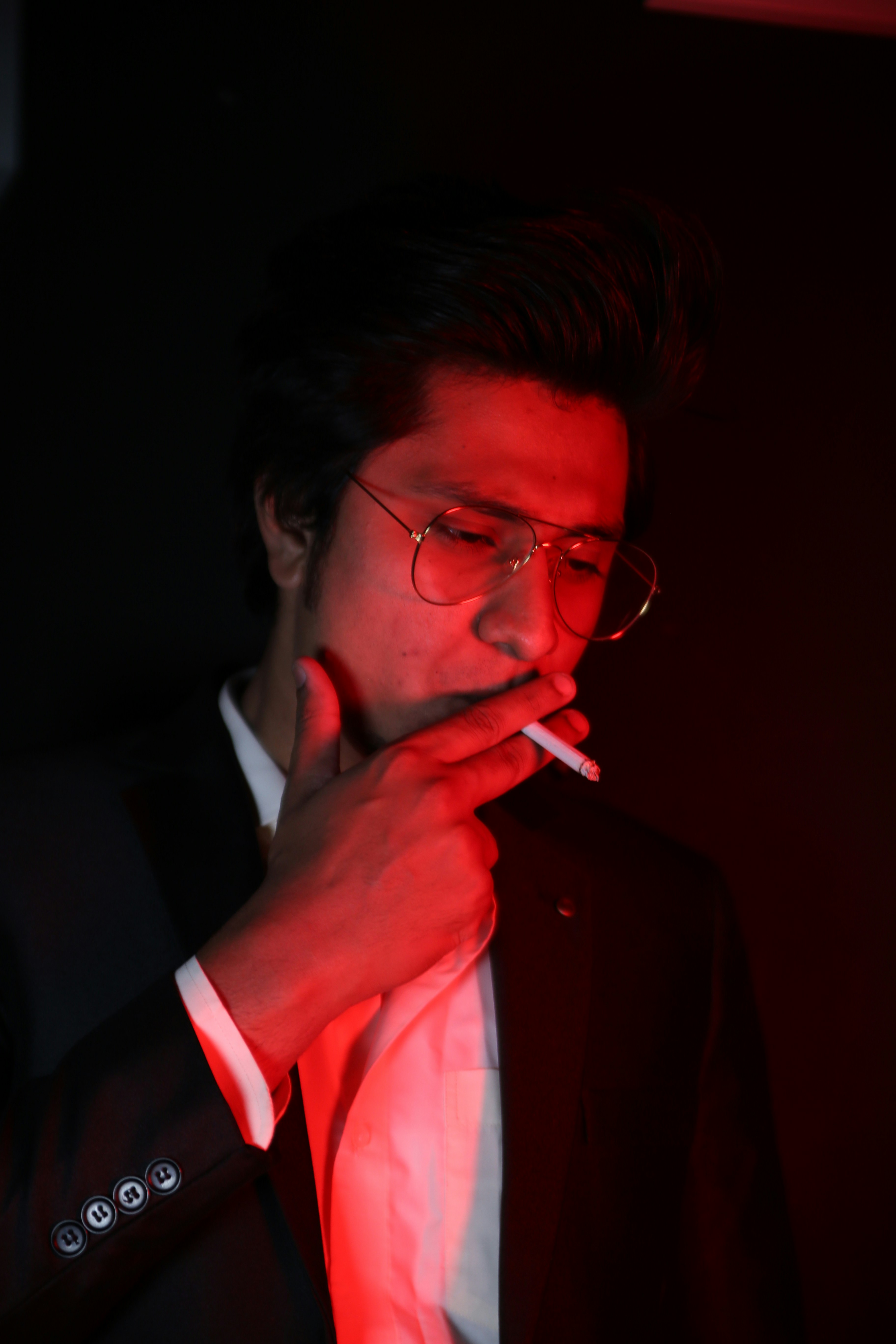 Crimson Glow in Shadow: A Suited Man Smokes in Low Light