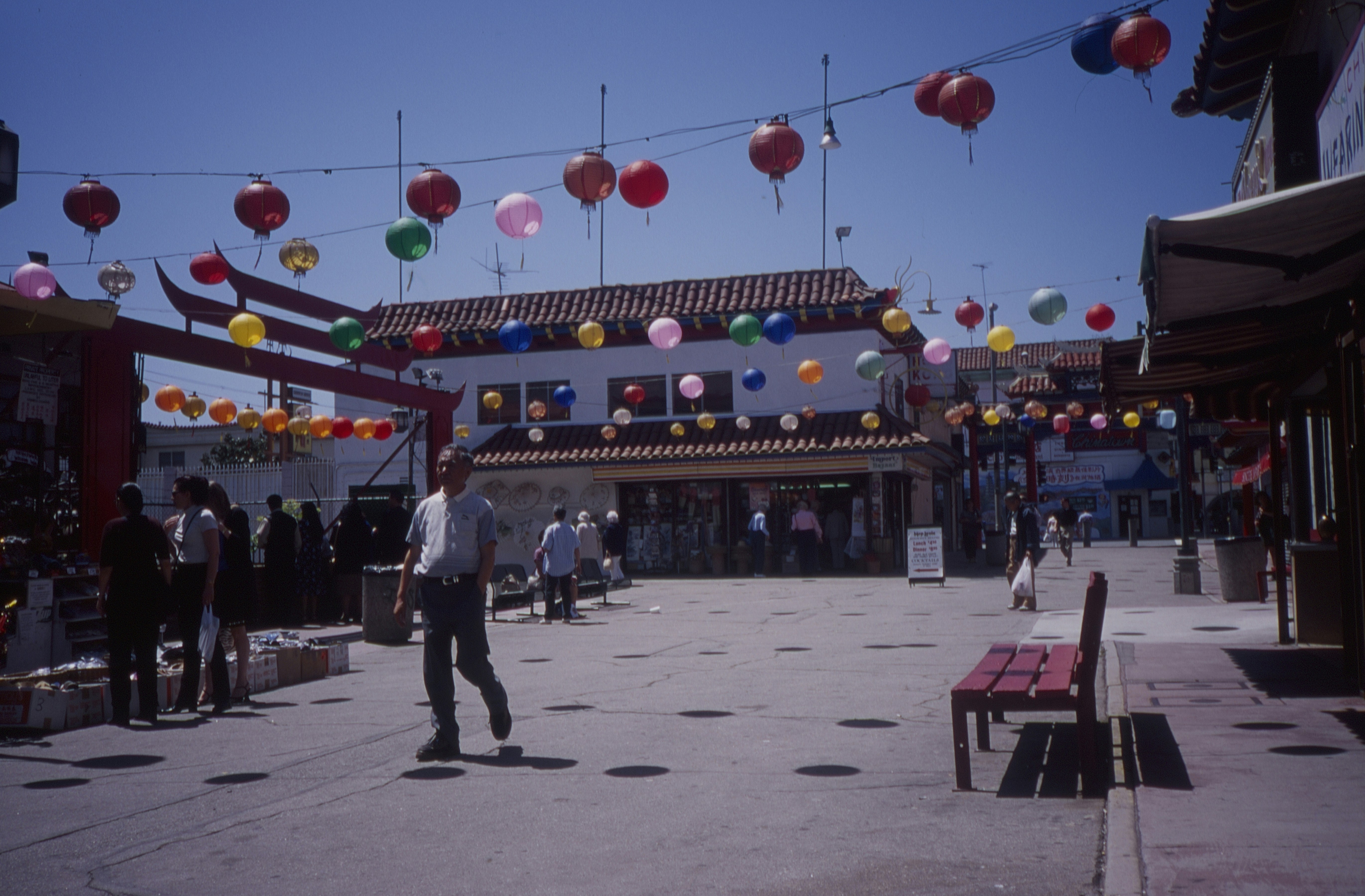 Colorful lanterns suspended over a bustling street in Chinatown on a sunny day.