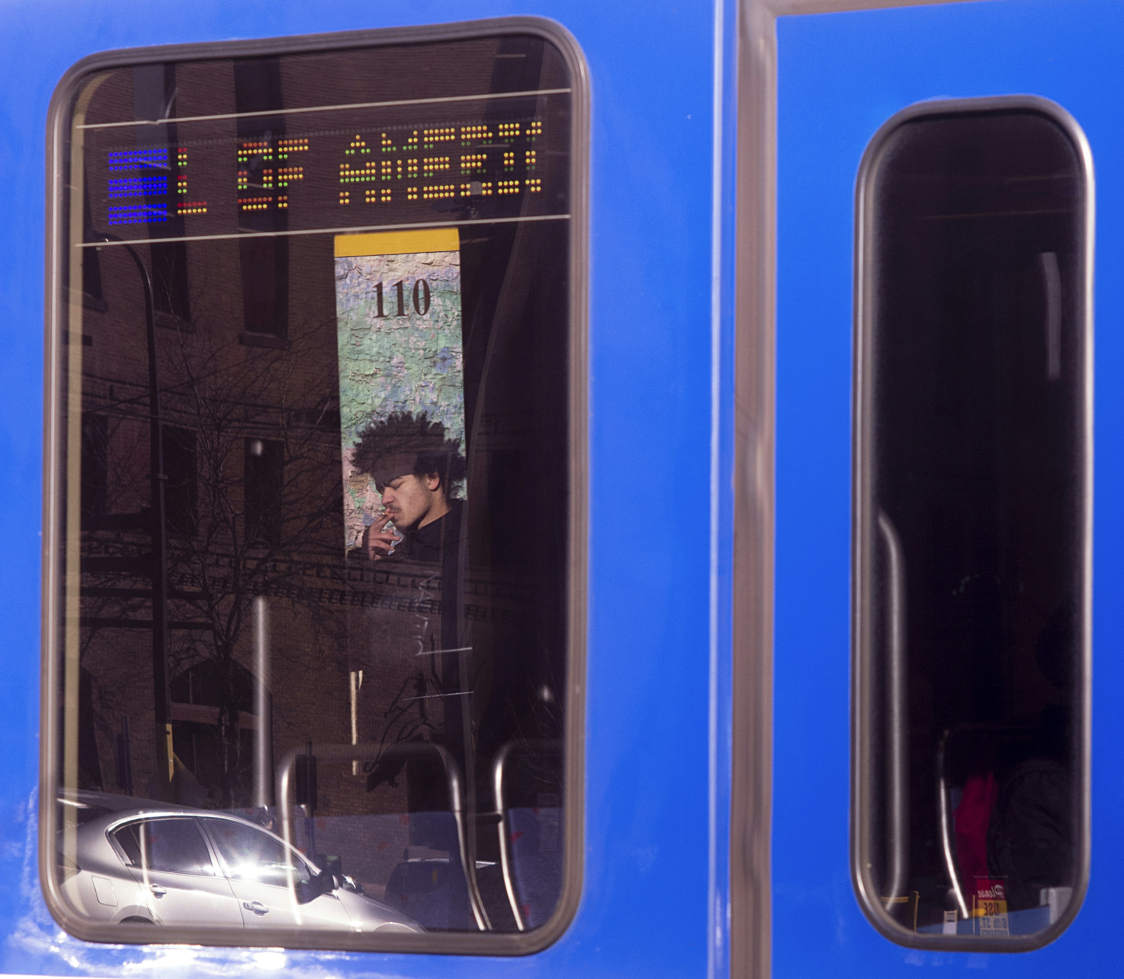 A reflection of a man and transit information displayed on a train window, capturing the essence of city commuting.