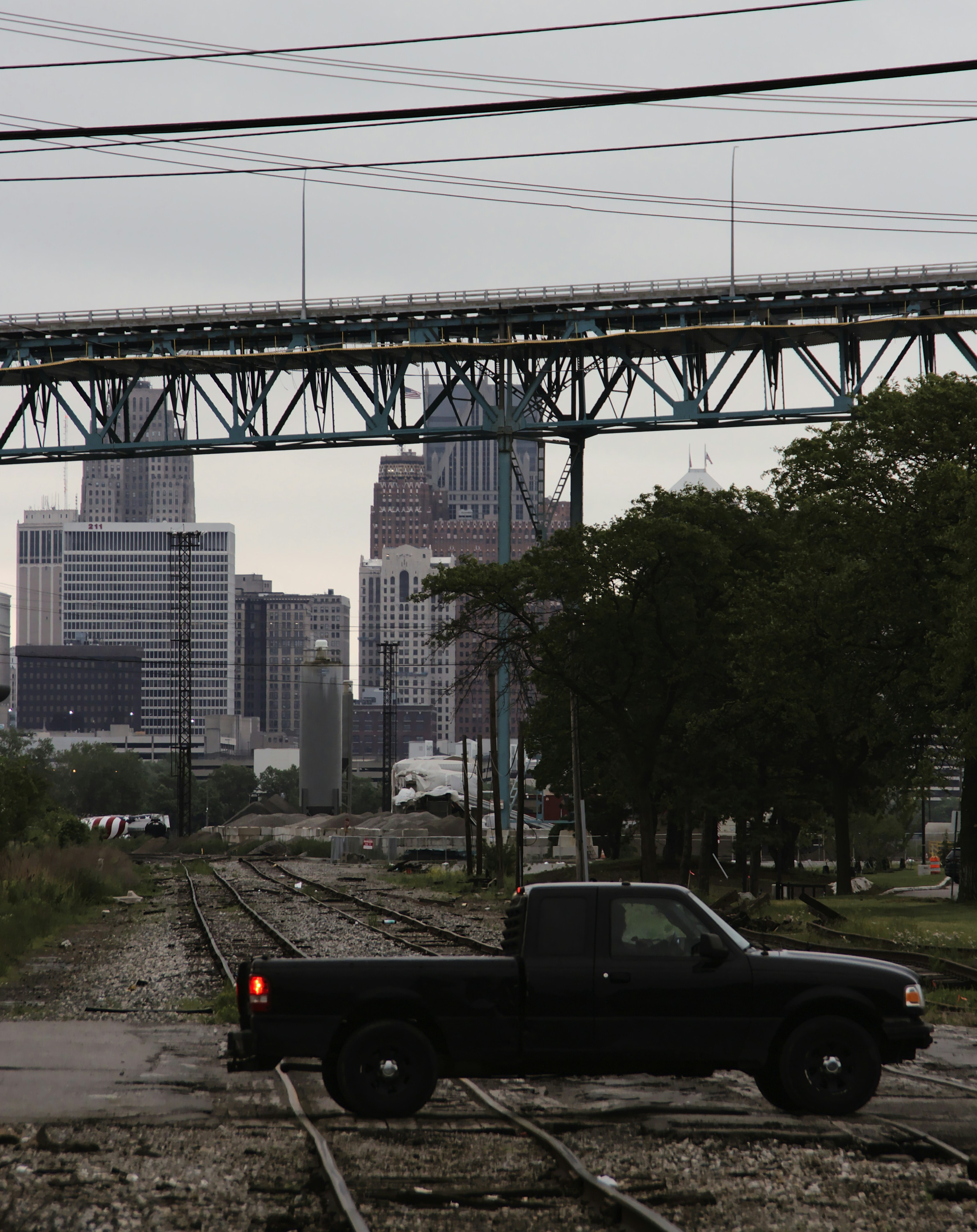 Black crew cab pickup truck on road near green trees and high rise ...
