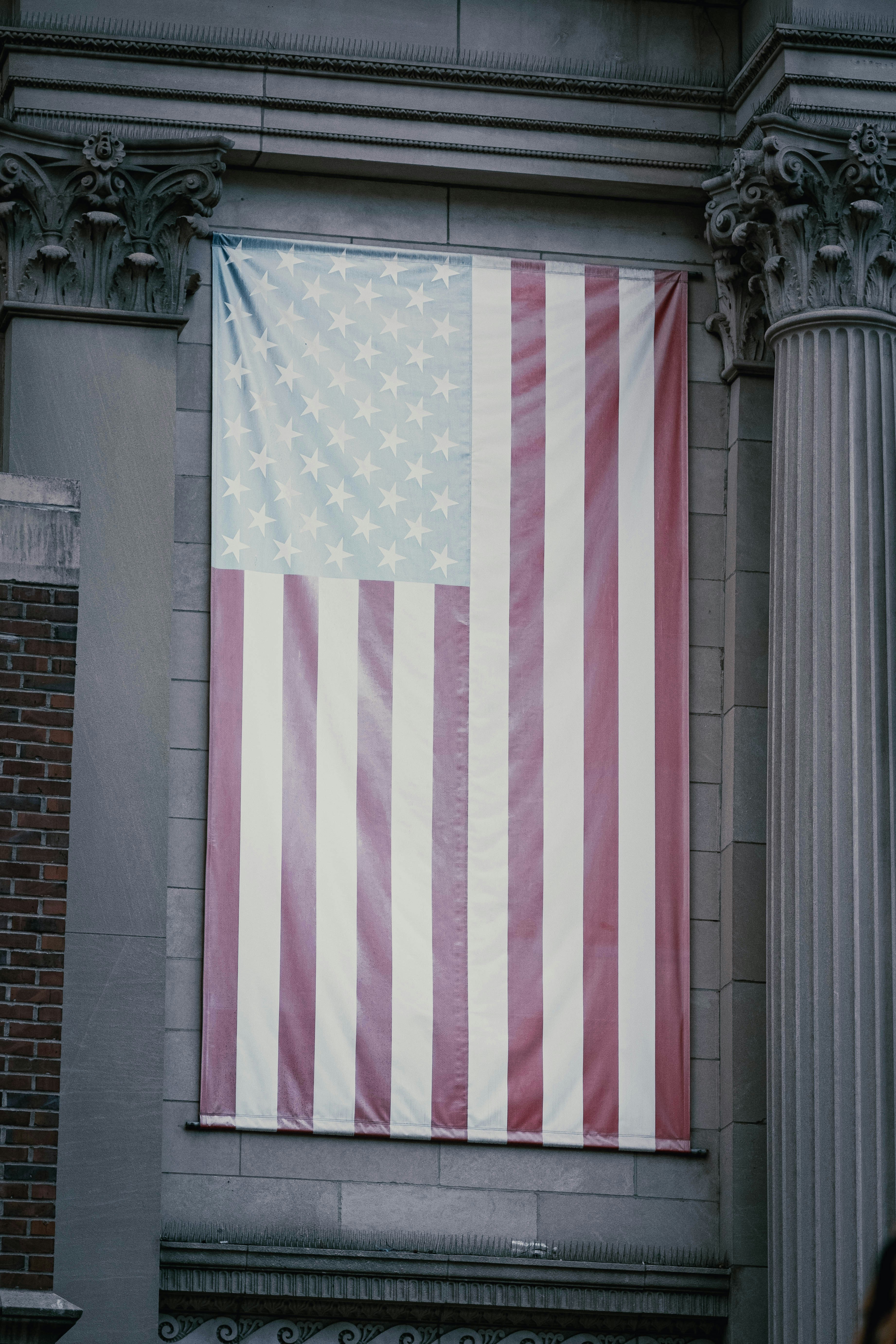 Large American flag banner displayed on a historic building, showcasing the blend of national pride and architectural elegance.
