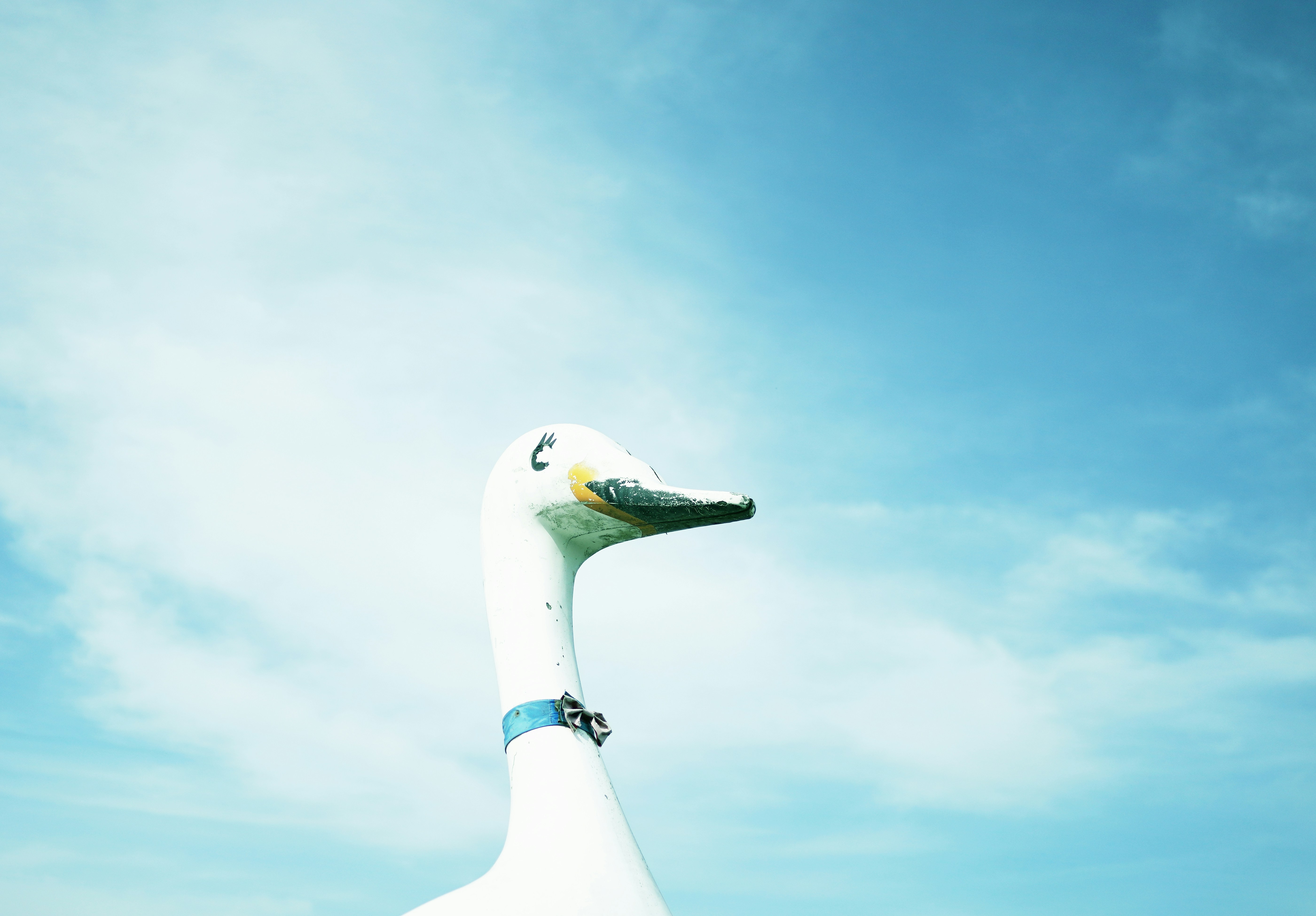 A large white duck sculpture stands against a bright blue sky, showcasing its playful design and vibrant colors.