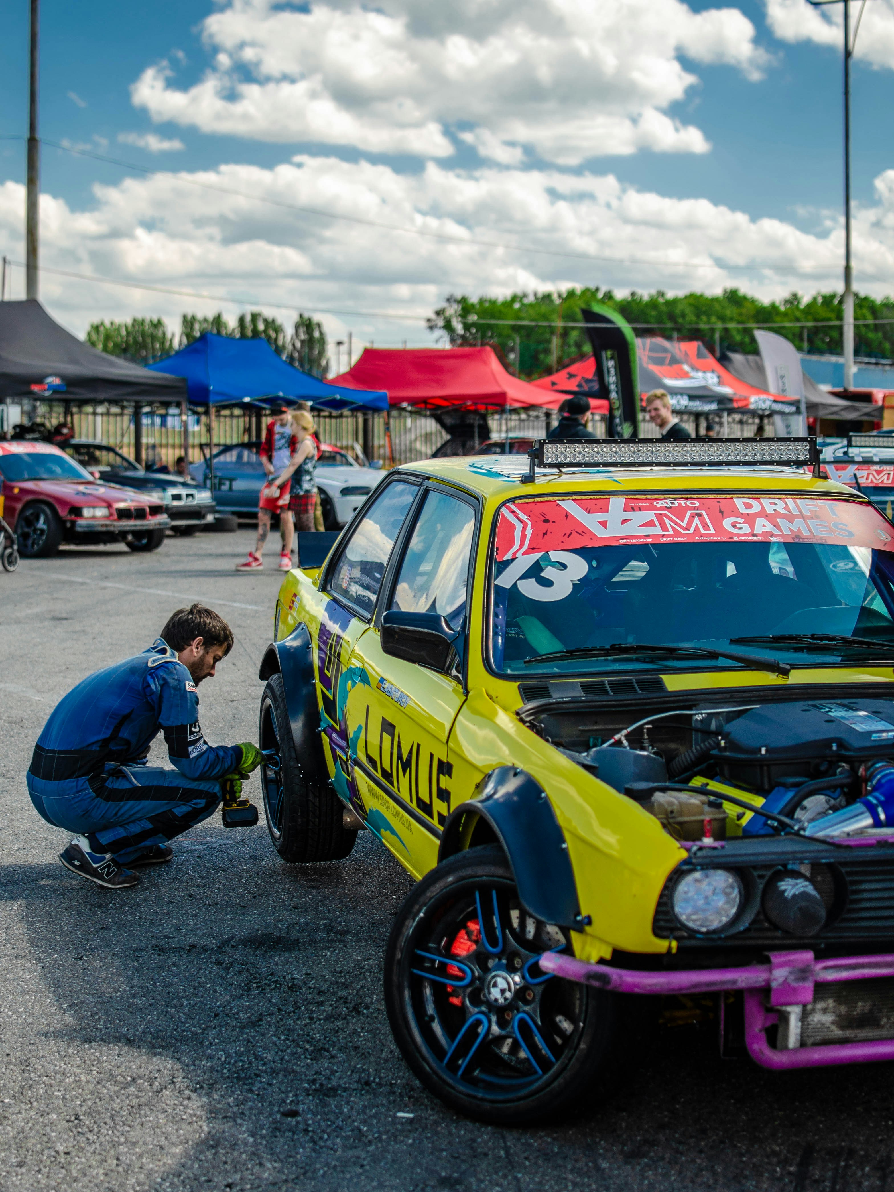 Yellow race car at a pit stop being serviced under a bright weekend sky
