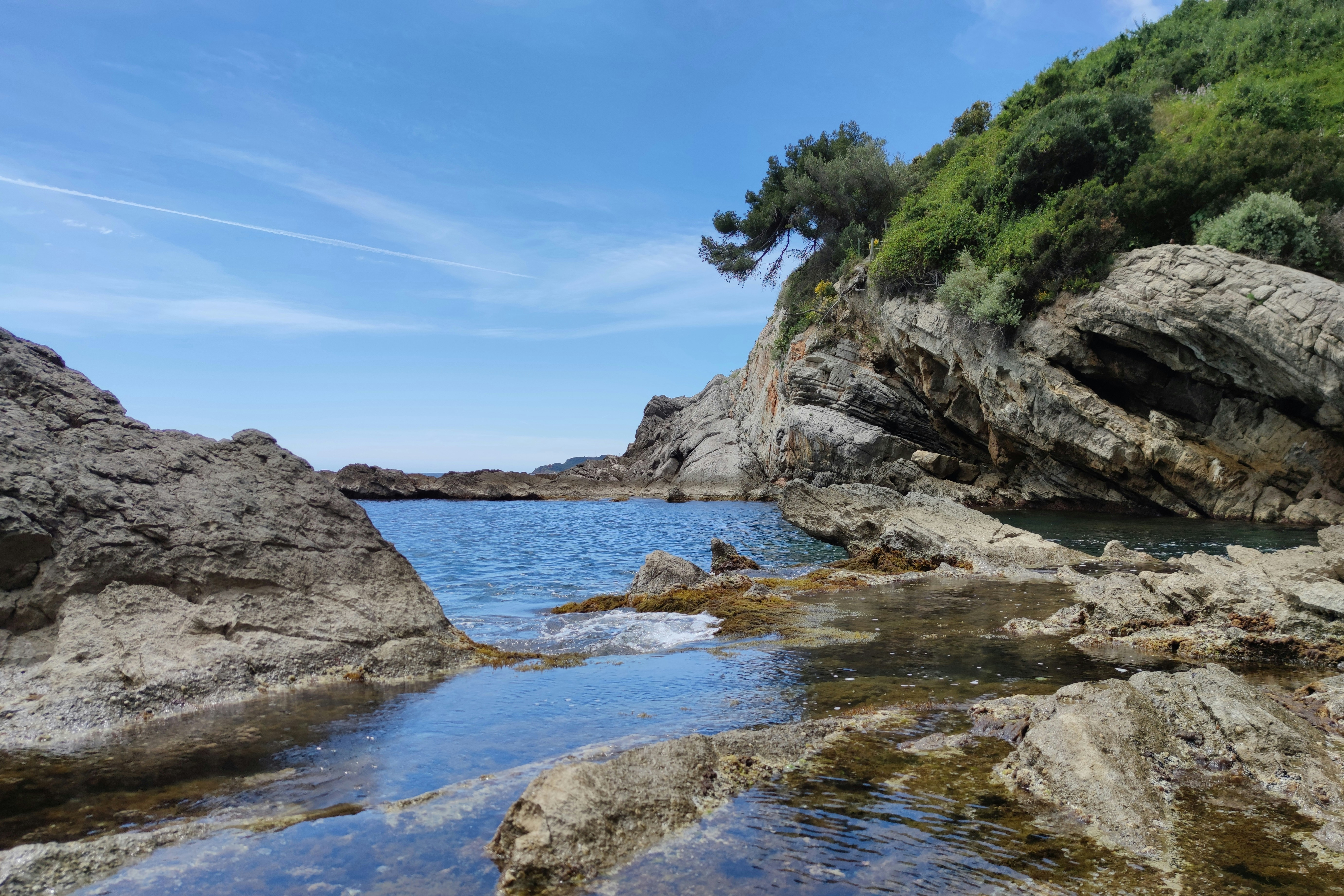 Rocky shoreline meets tranquil waters under a clear blue sky, showcasing the beauty of coastal landscapes.