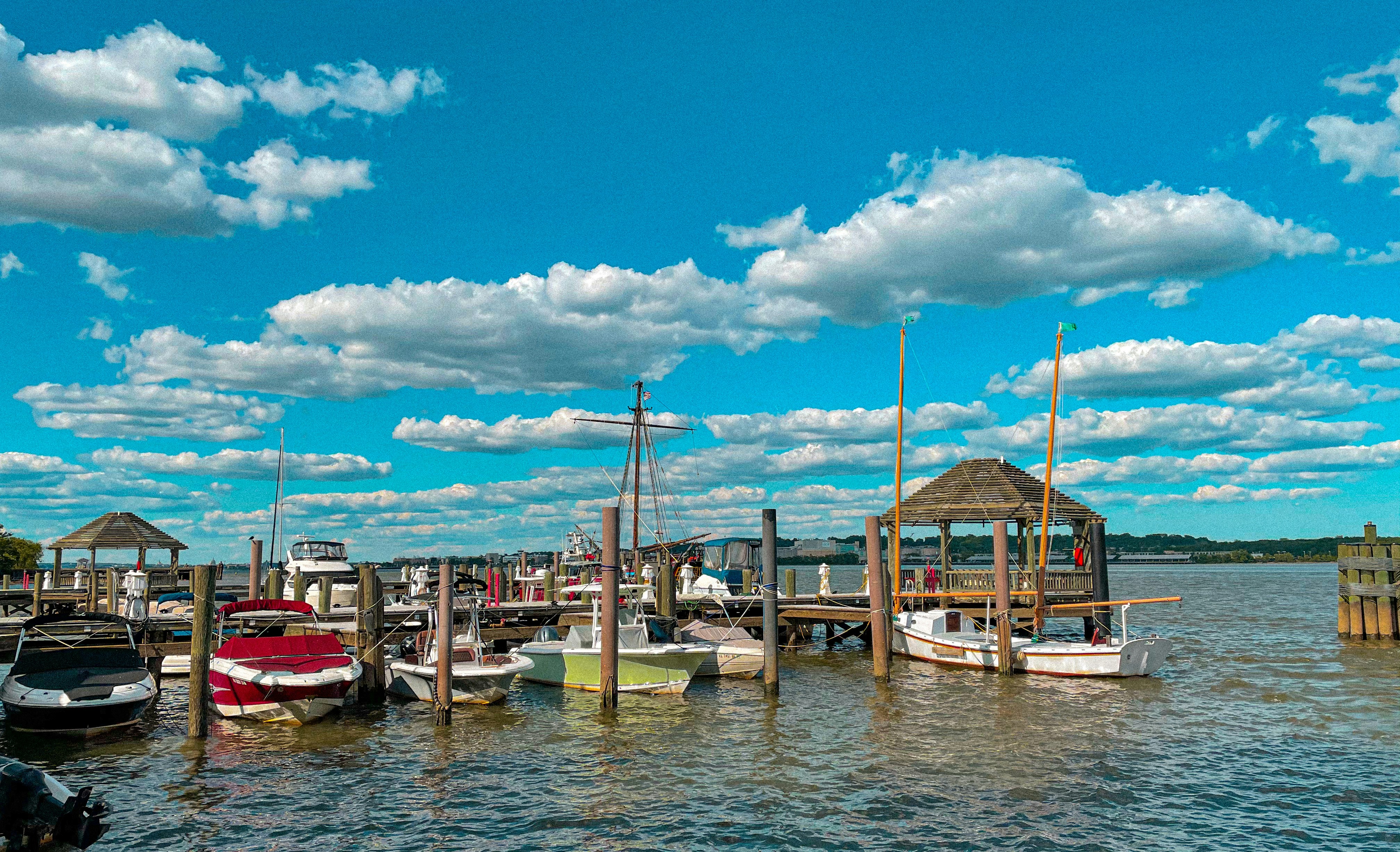 Docked boats resting peacefully under a vibrant blue sky with scattered white clouds.