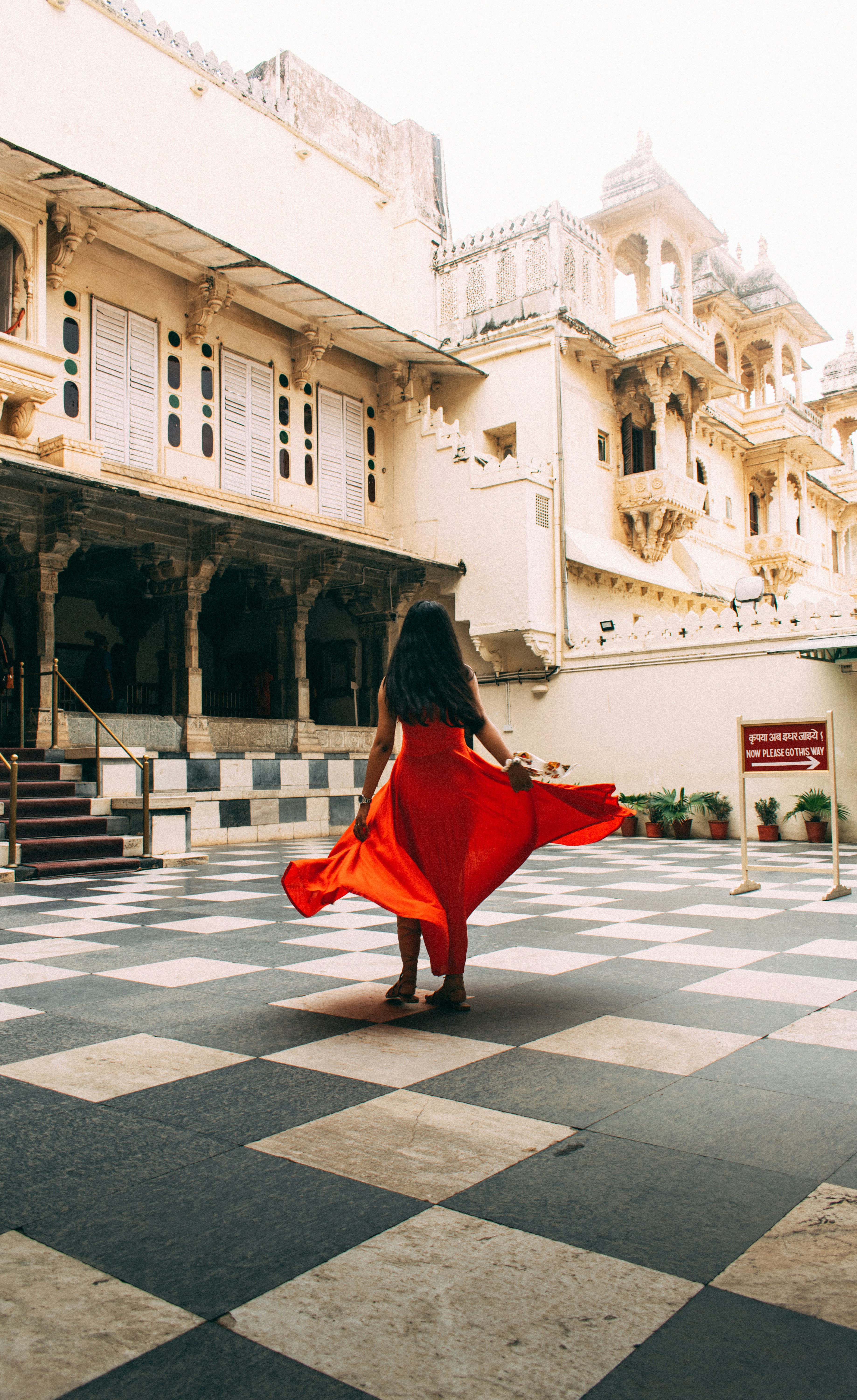 Red Dress, White Palace: A dancer in motion within a sunlit courtyard