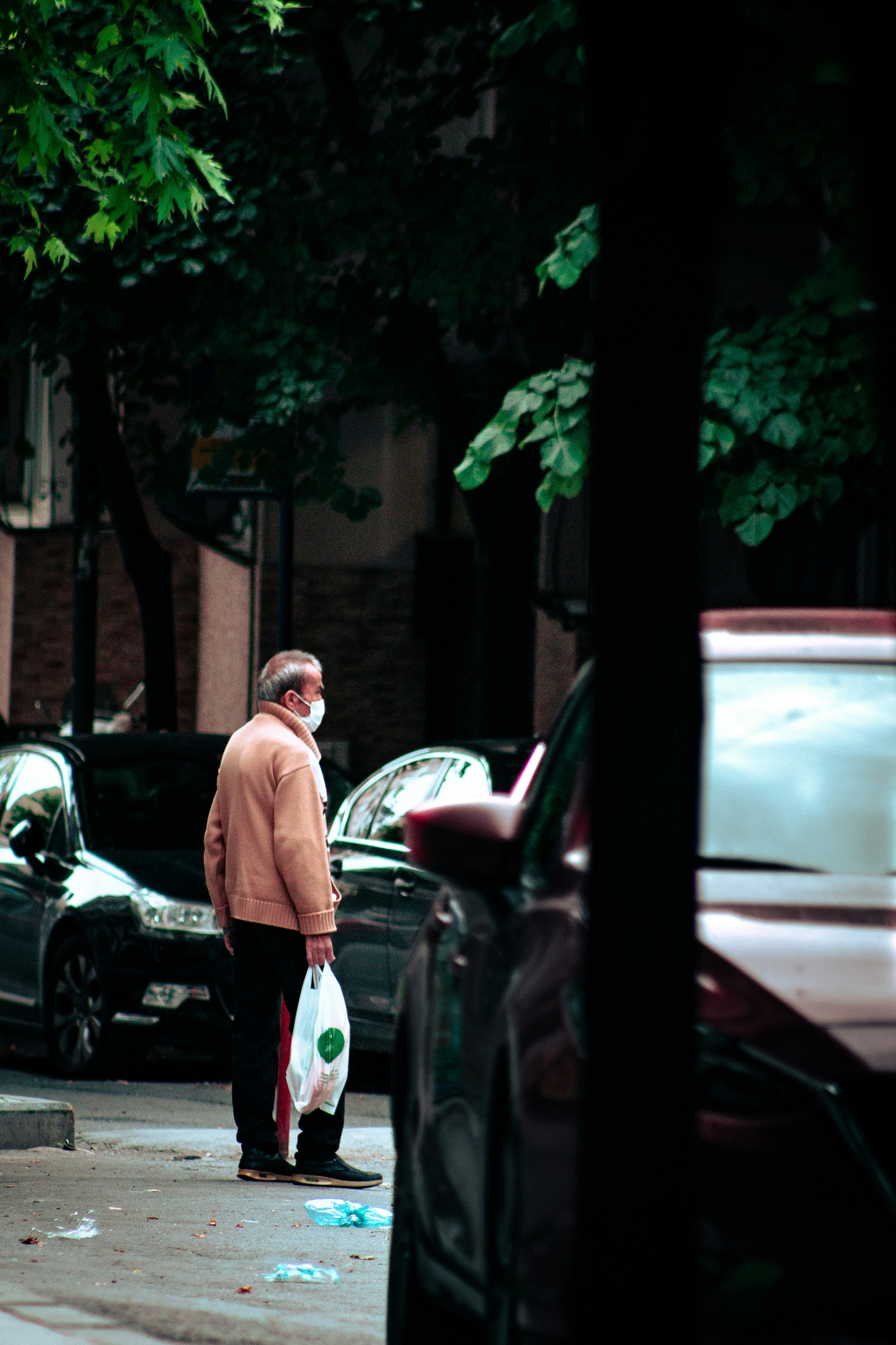 Masked Pause by Parked Cars on a Quiet City Street