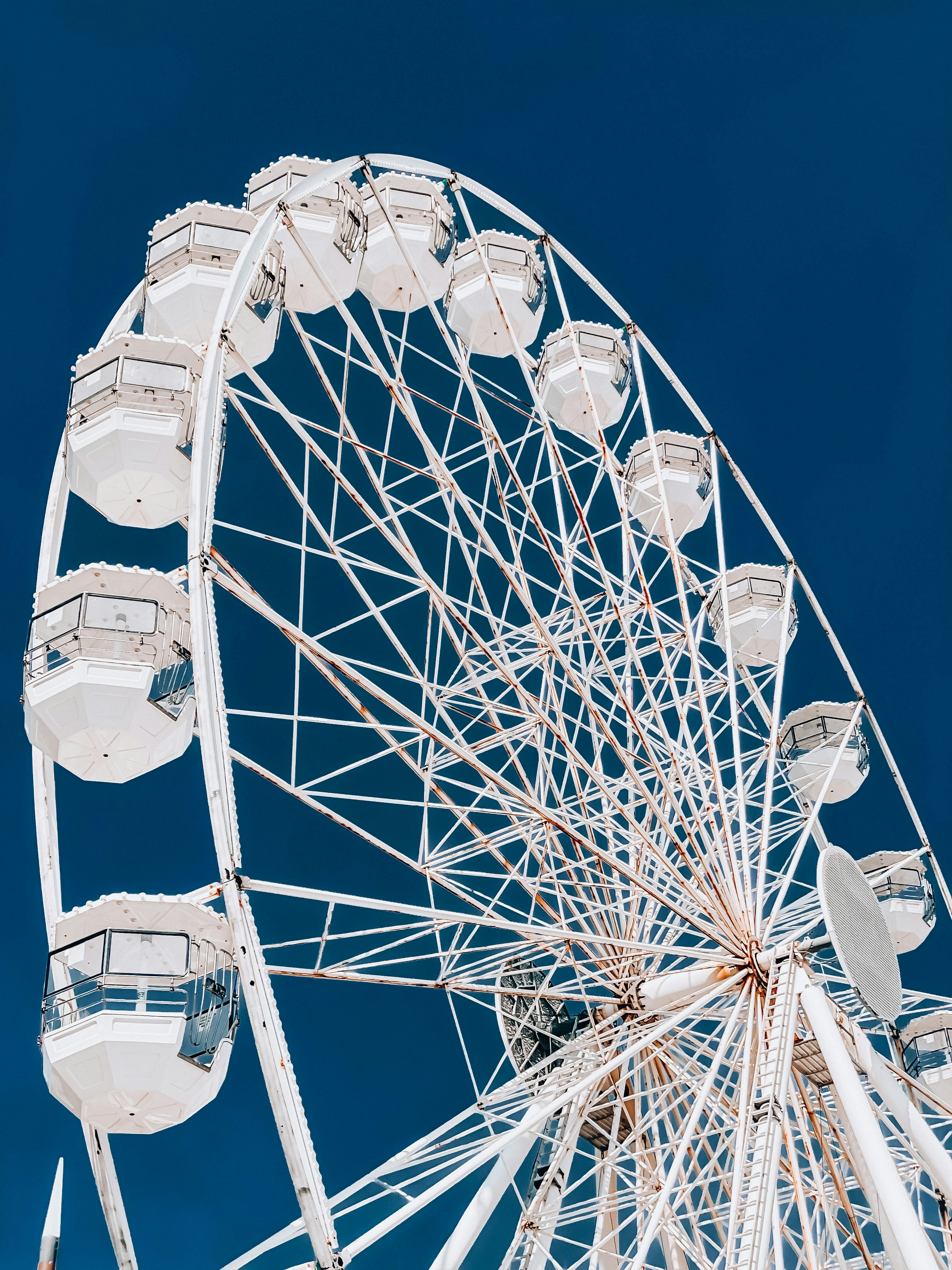 A towering Ferris wheel against a clear blue sky, showcasing its white cabins and intricate structure.
