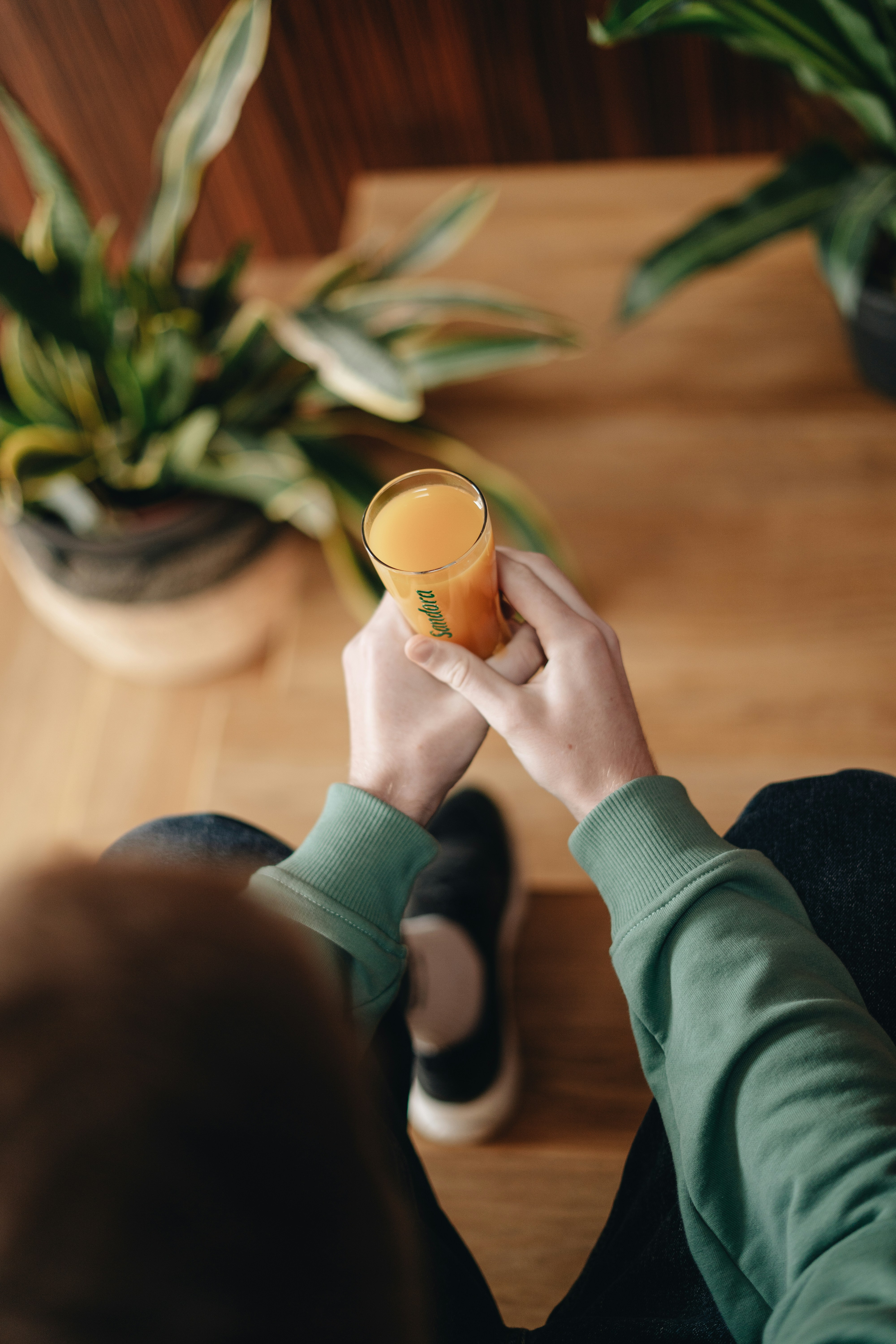 A Quiet Moment: Hands Cradling a Glass of Juice in a Cozy Corner
