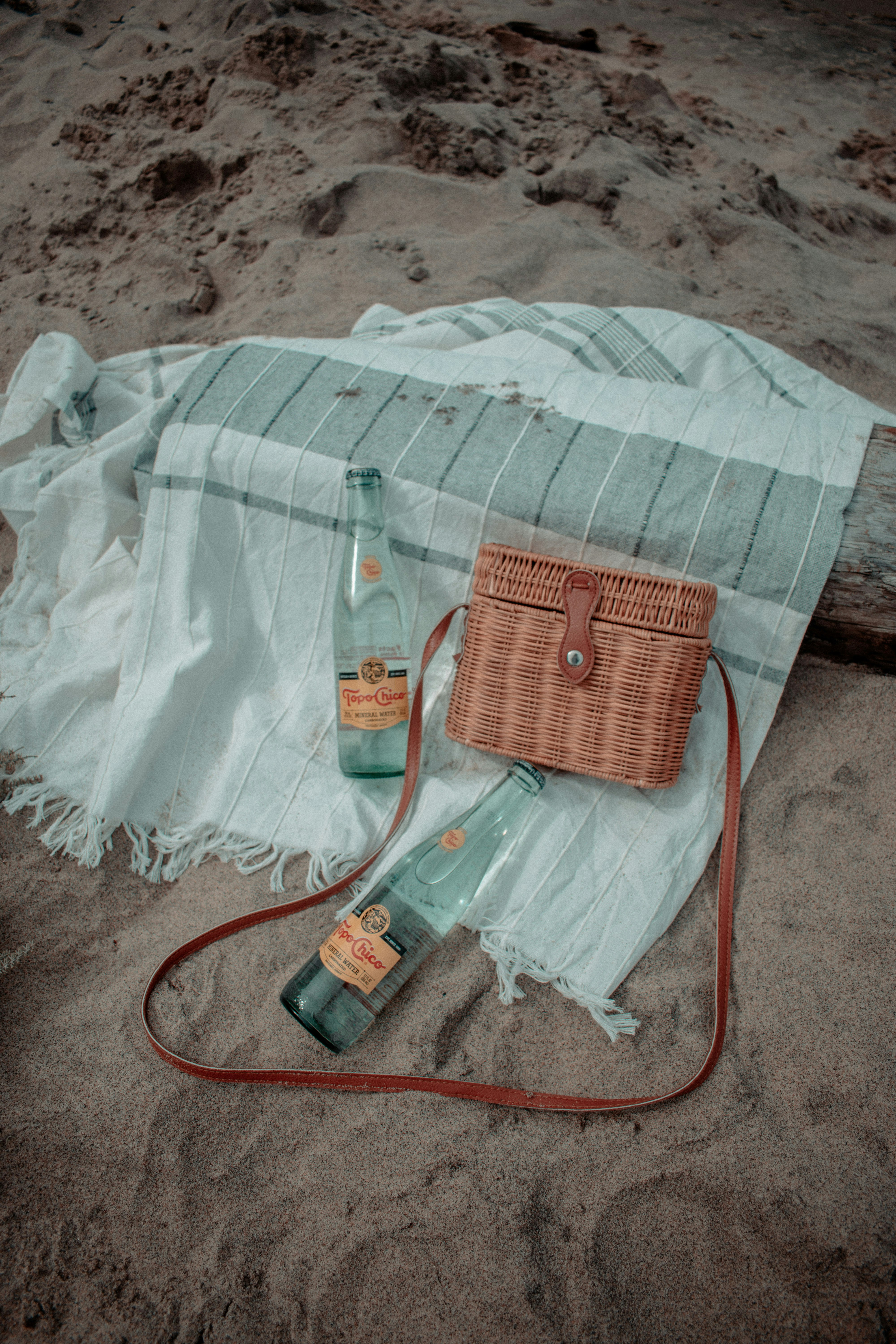 Sunstruck Picnic: A Wicker Basket and Green Bottles on a Striped Beach Throw
