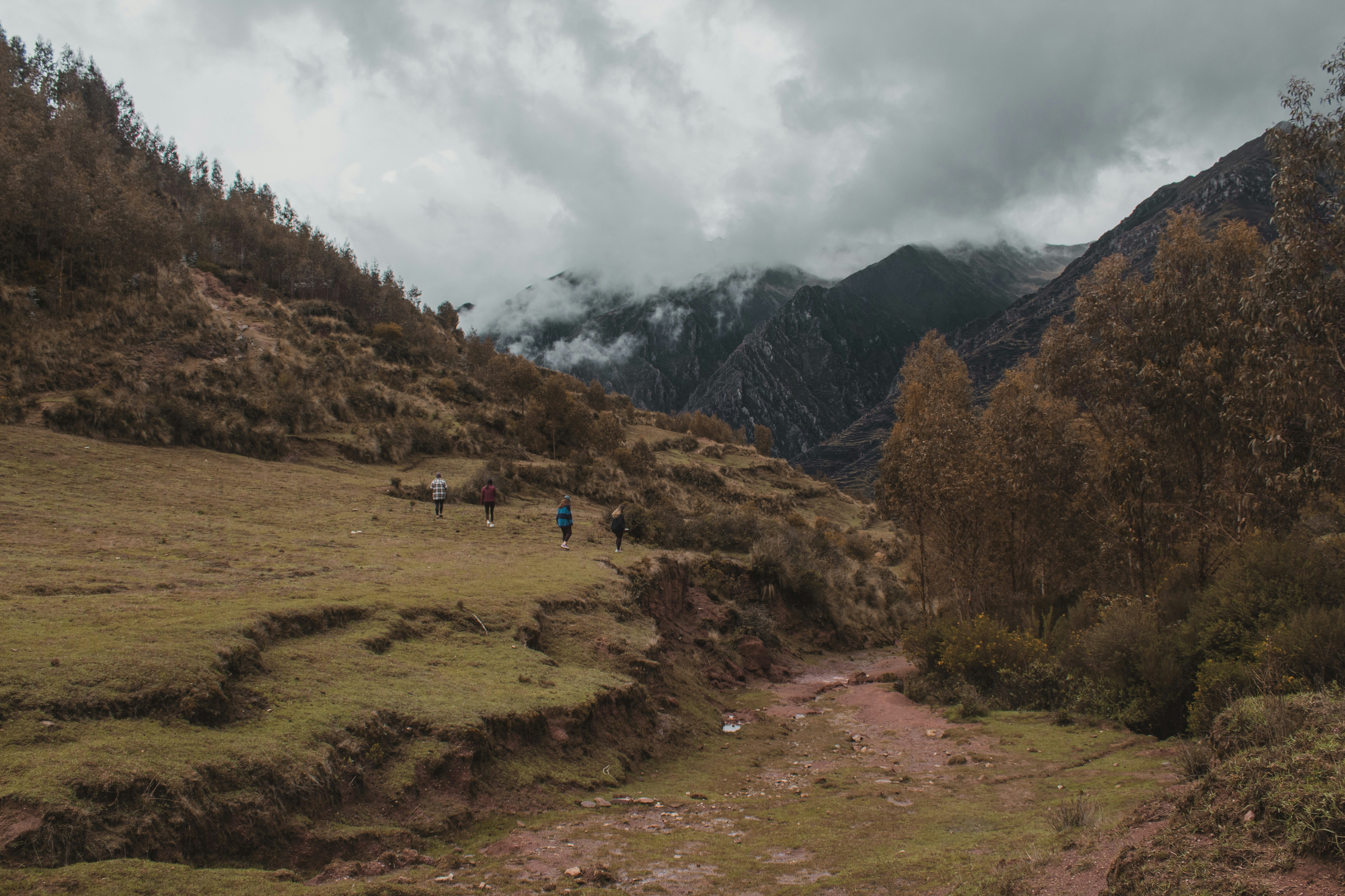 Hikers traverse a rugged landscape beneath a dramatic sky in the Andes mountains. The scene captures the essence of adventure in a remote setting.