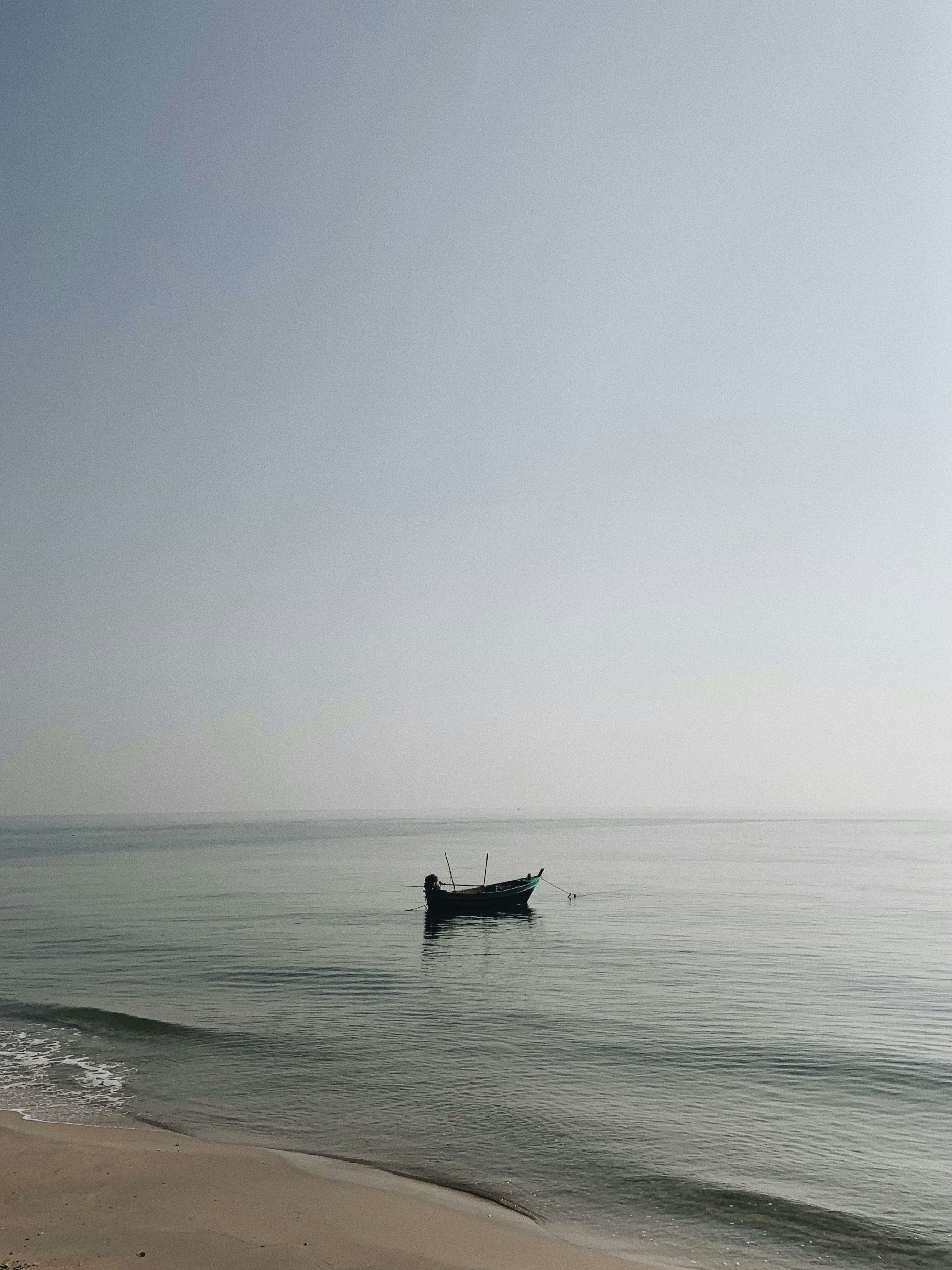 Lone Vessel Adrift on a Glassy Sea at a Pale Horizon