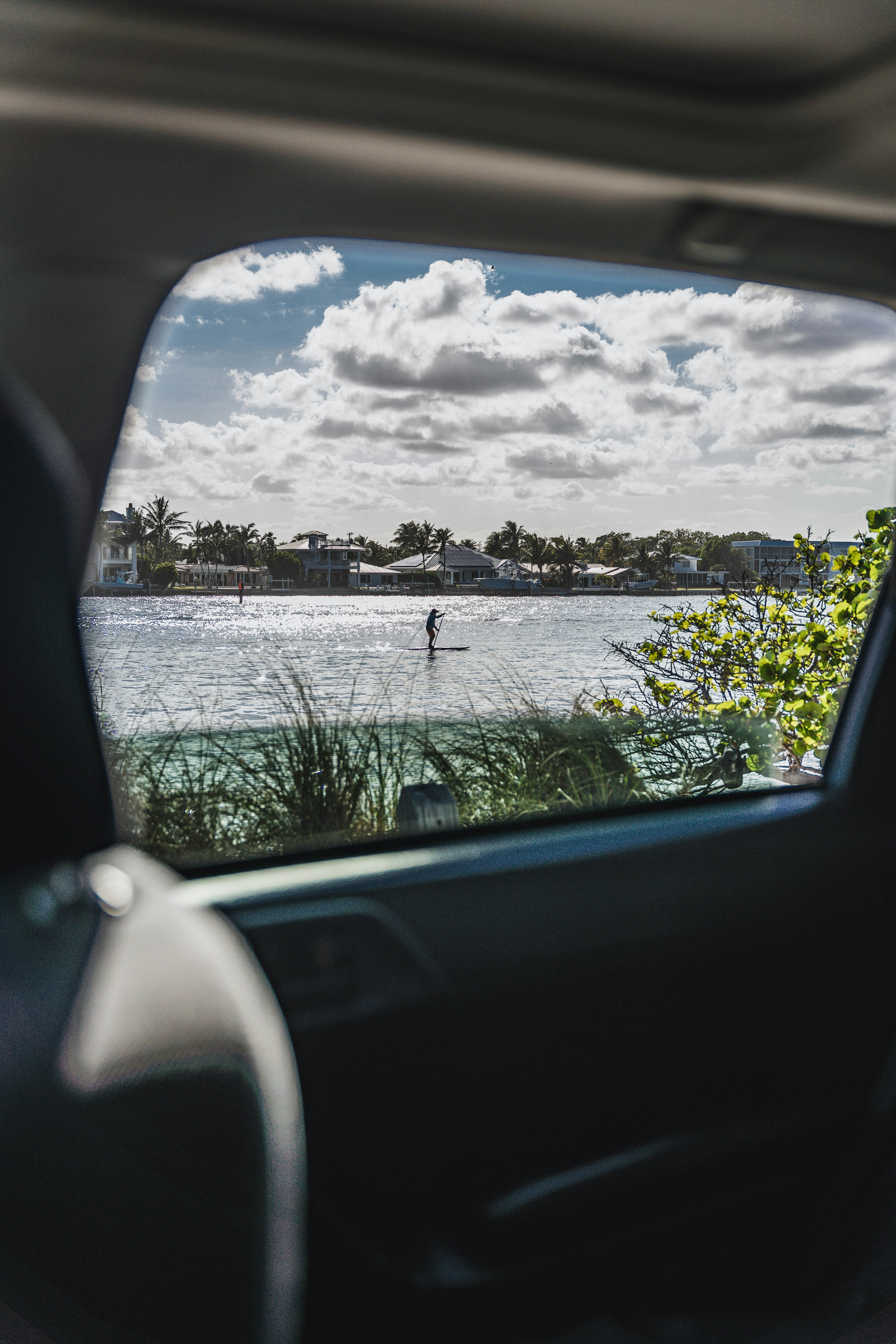 Window to a Quiet Wake: Paddleboarder Across Sunlit Shore