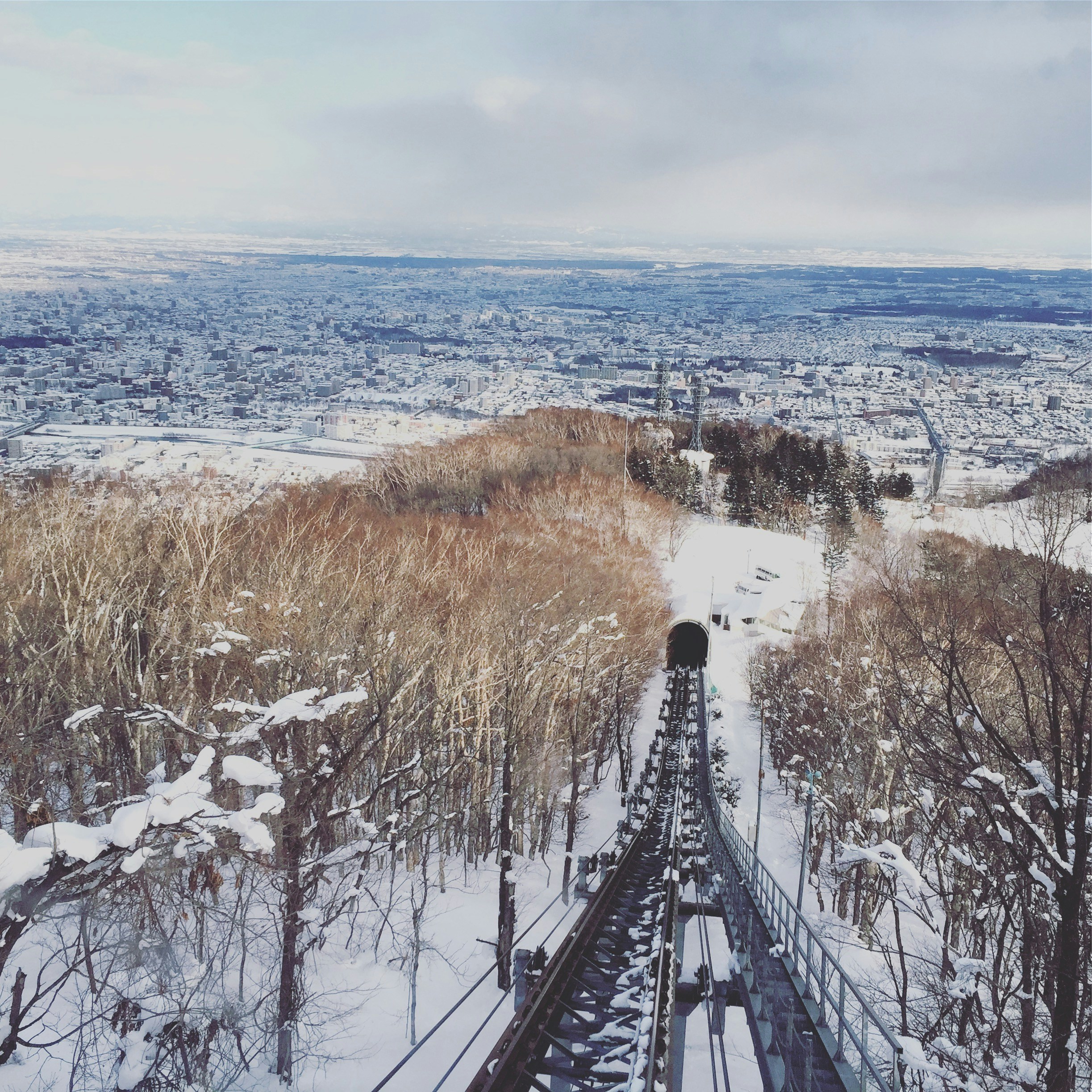 Ridge to Tunnel: Snow-Lined Rails Framing a Distant City