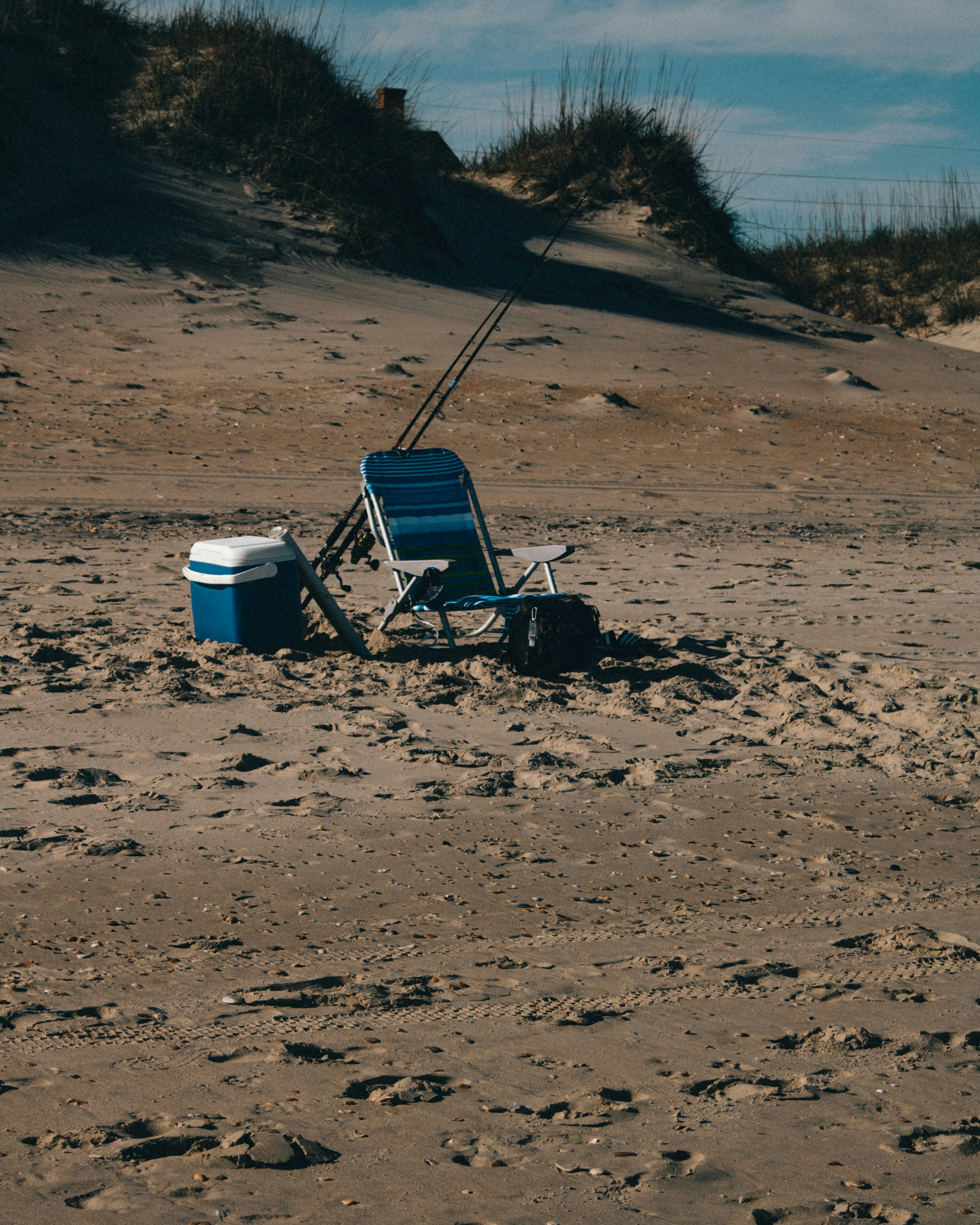 Blue Beach Chair by the Shore: Fishing Rods Resting in Quiet Dunes