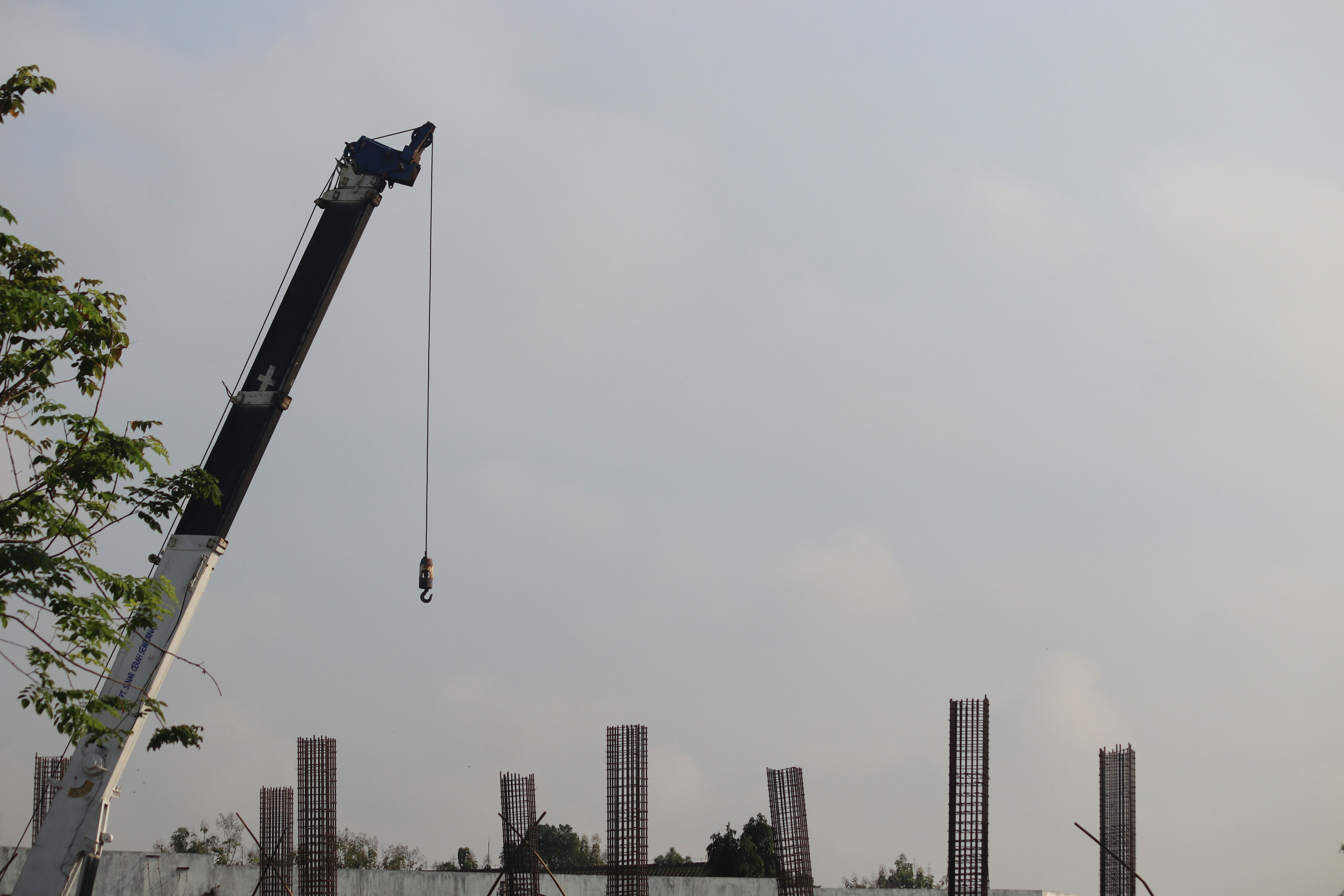 Diagonal Crane Hook Over a Quiet Industrial Skyline