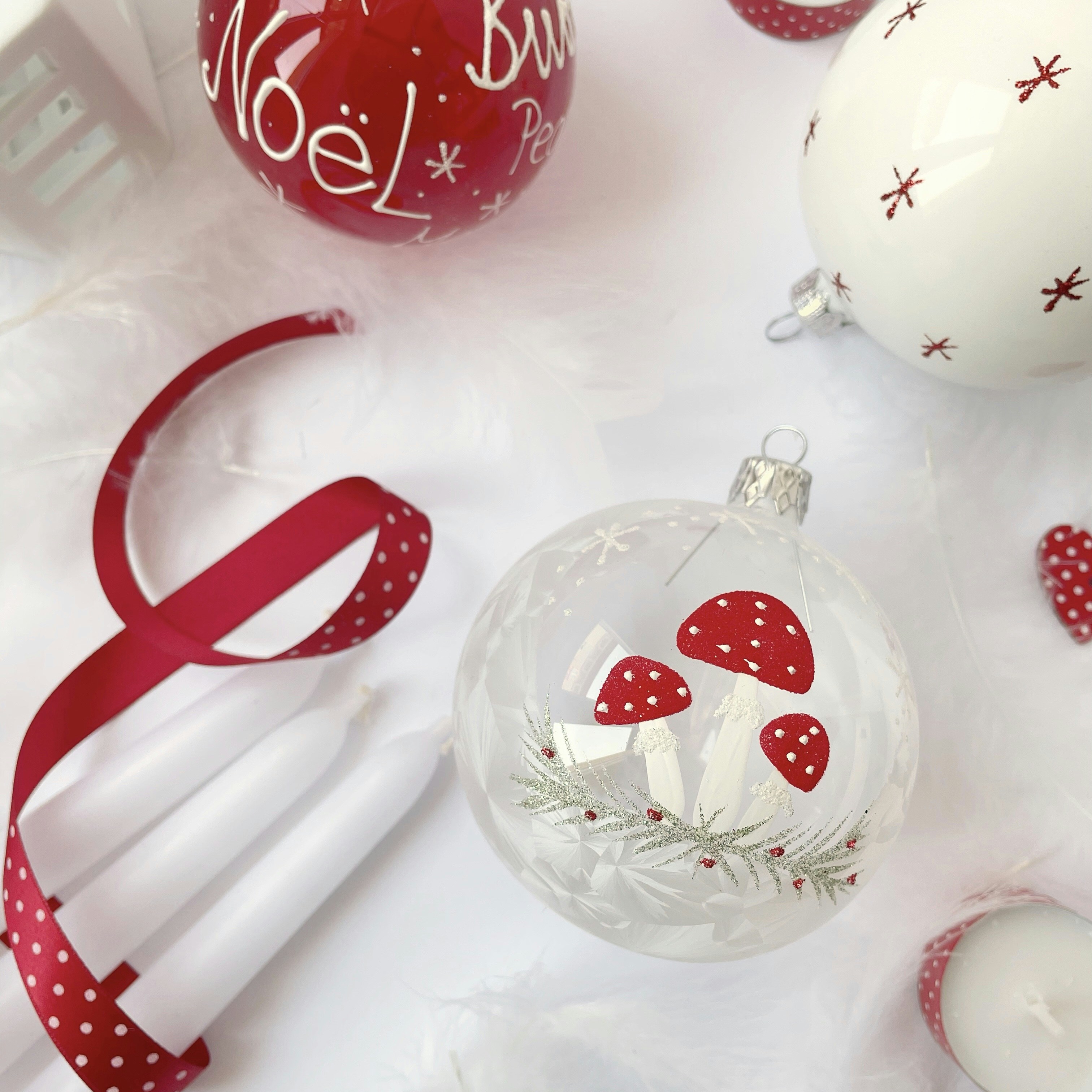 Crystal Ornament with Red Mushroom Motifs Anchors a White Holiday Still-Life