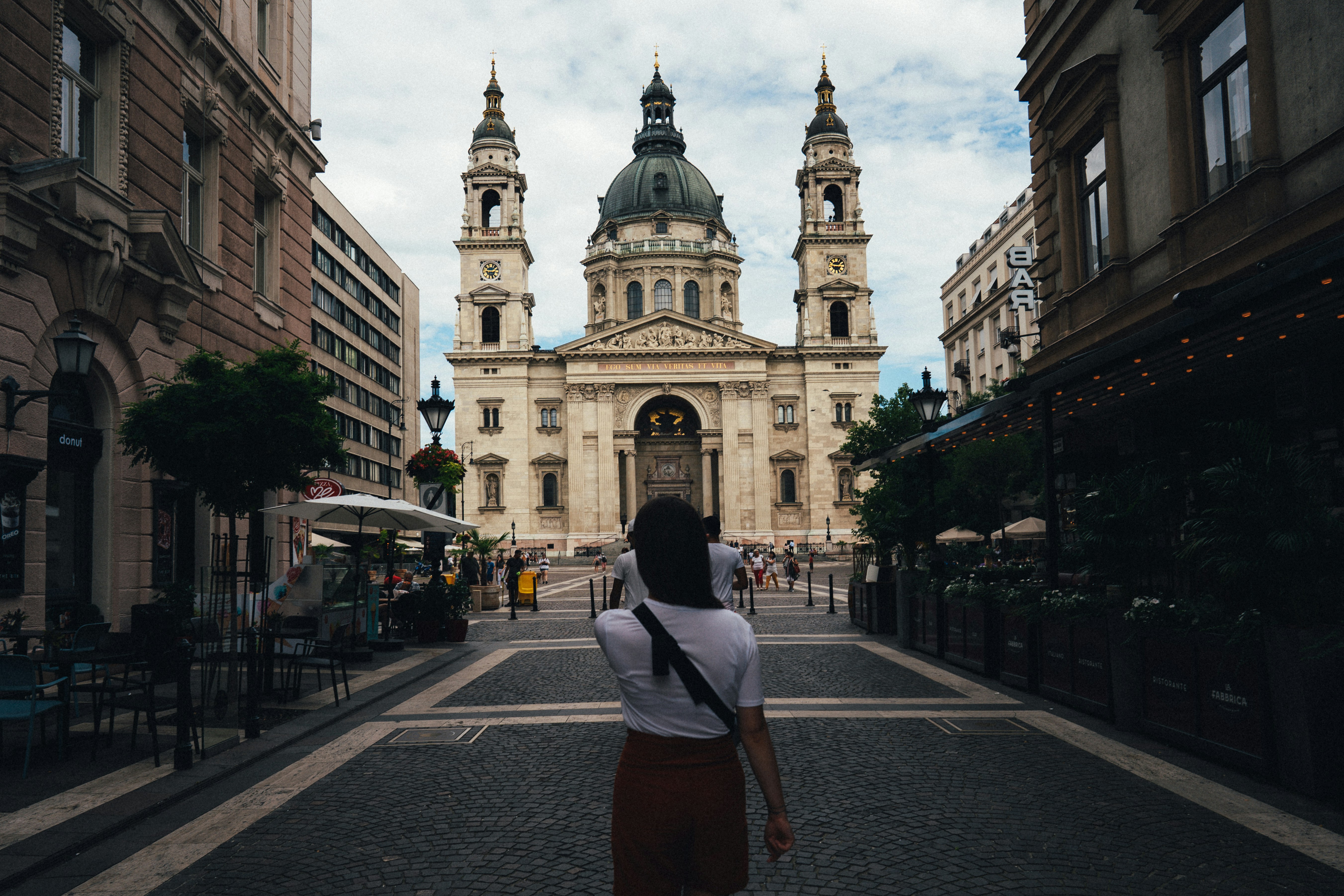 woman in white shirt and red skirt standing on sidewalk during daytime