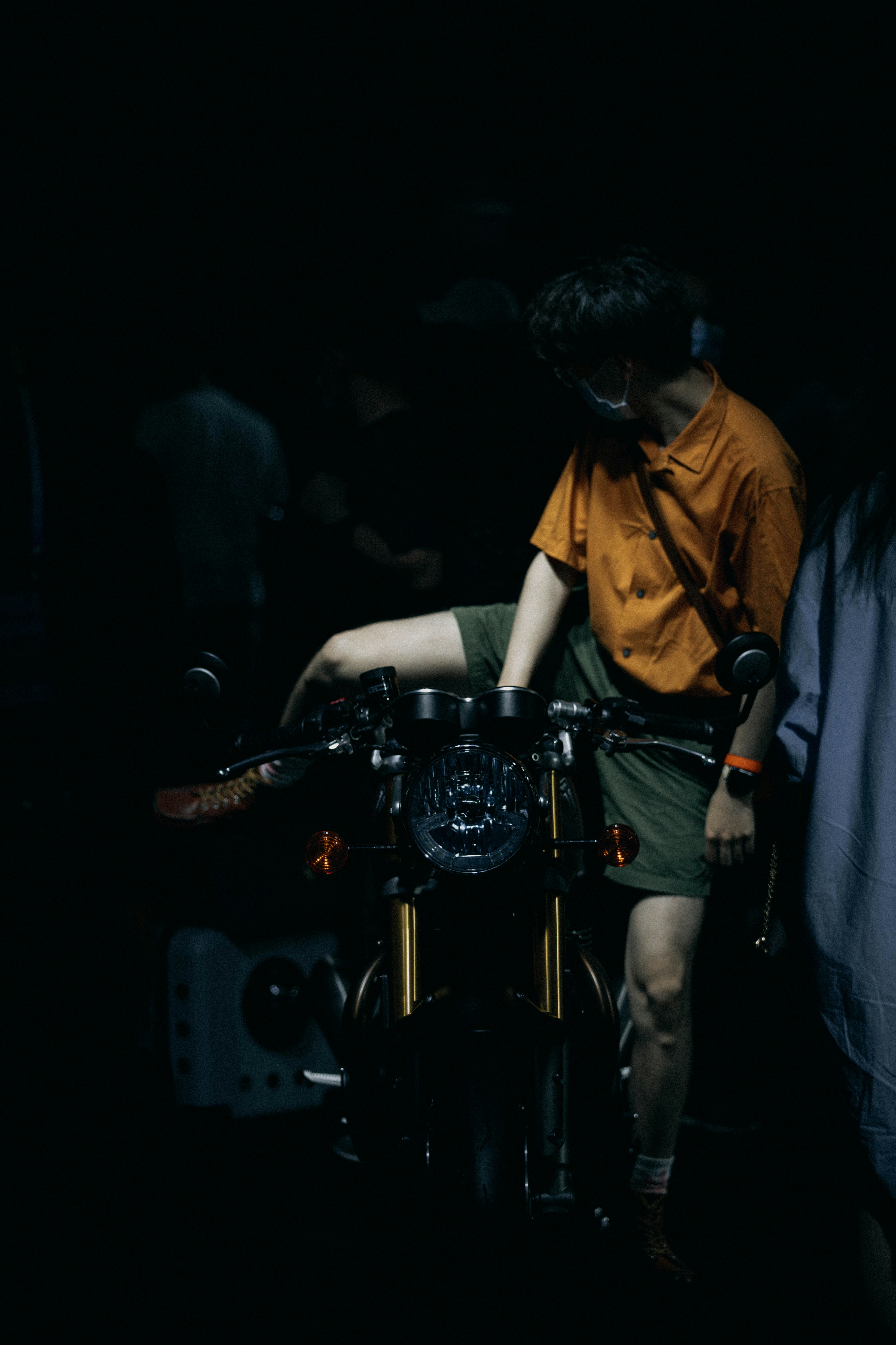 Orange-clad Rider at the Helm of a Dimly Lit Vintage Motorcycle