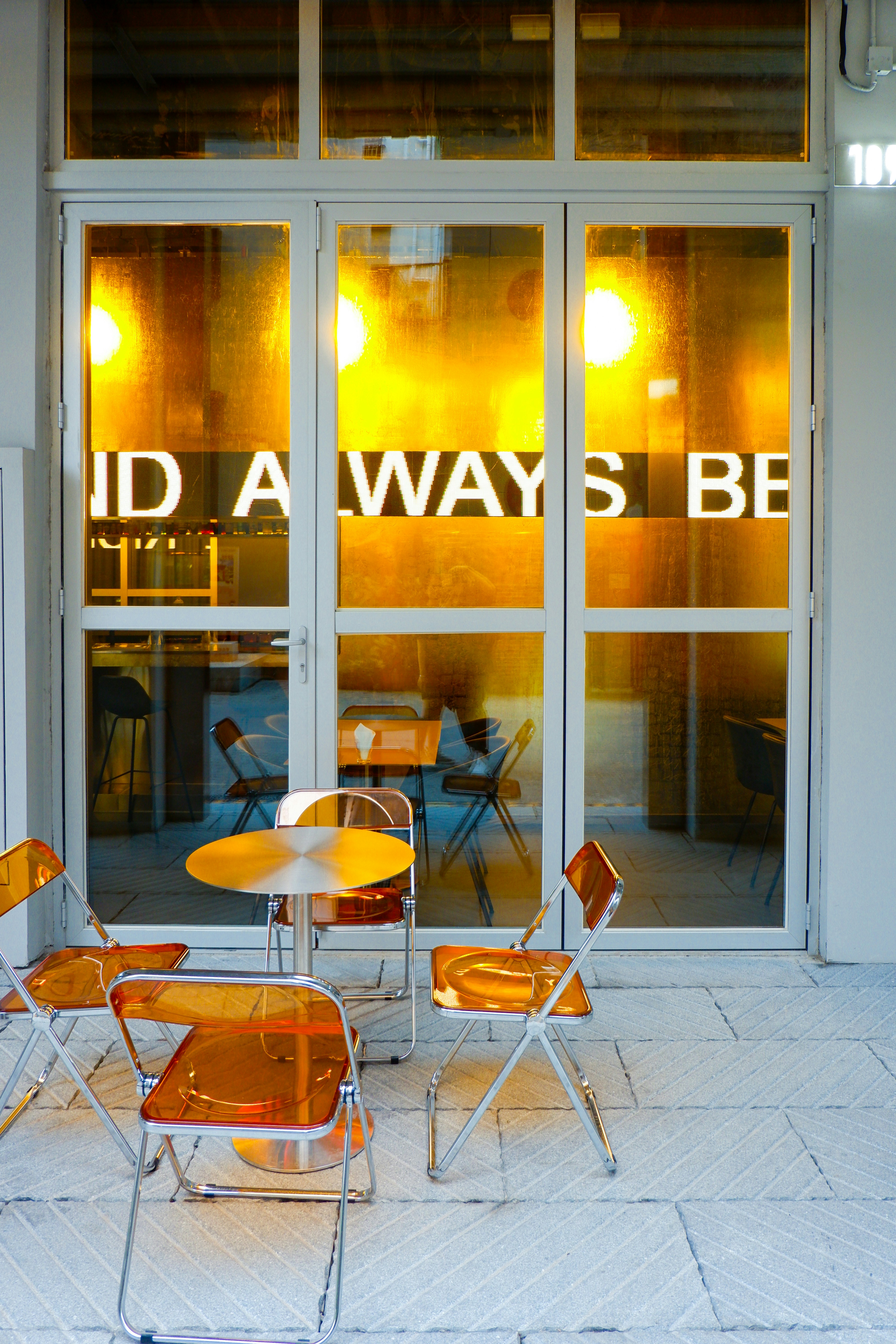 Amber Chairs Framed by Glass: Geometry of a Café Front