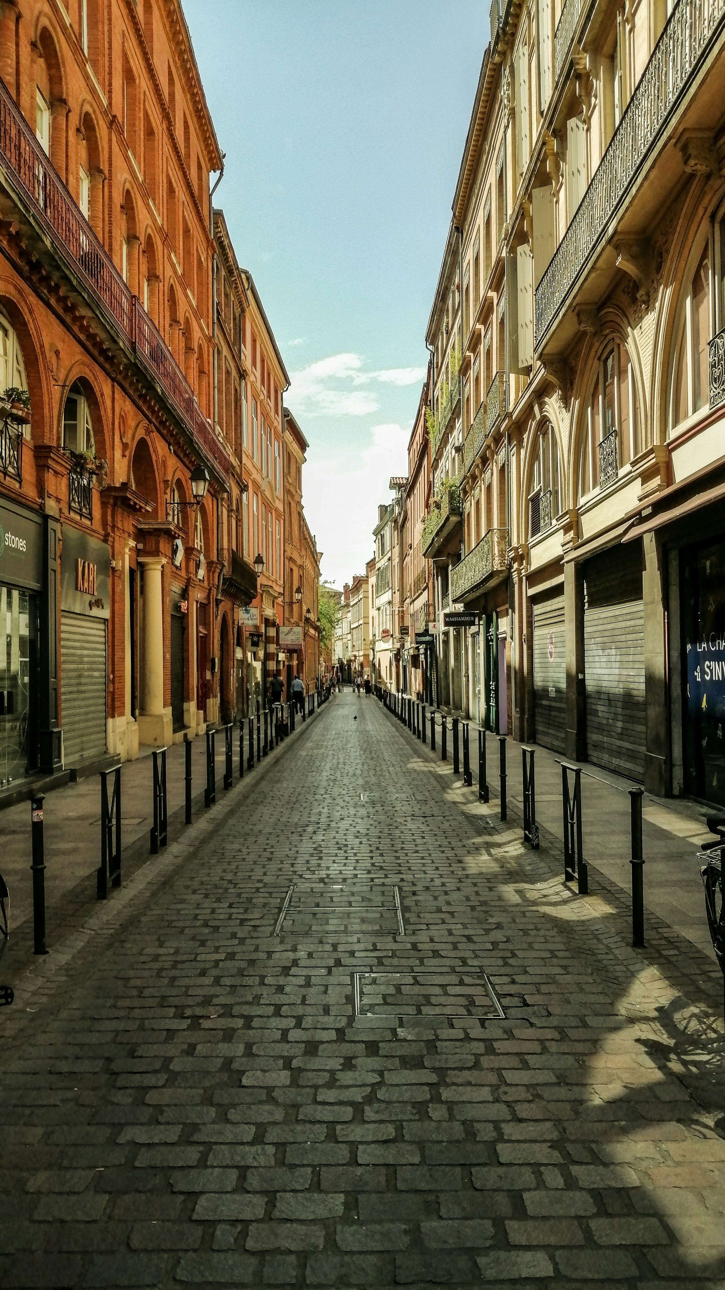 Cobblestone street lined with charming buildings in Toulouse, showcasing vibrant architecture and a serene atmosphere.