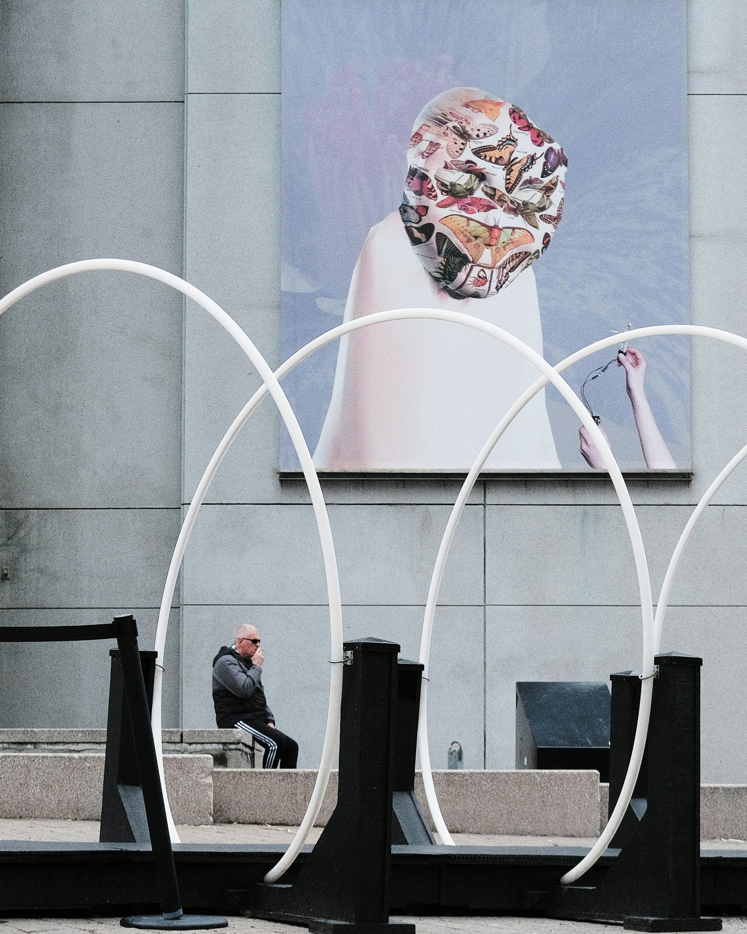 Circles Over Frames: A Quiet Moment Beneath Monumental Imagery
