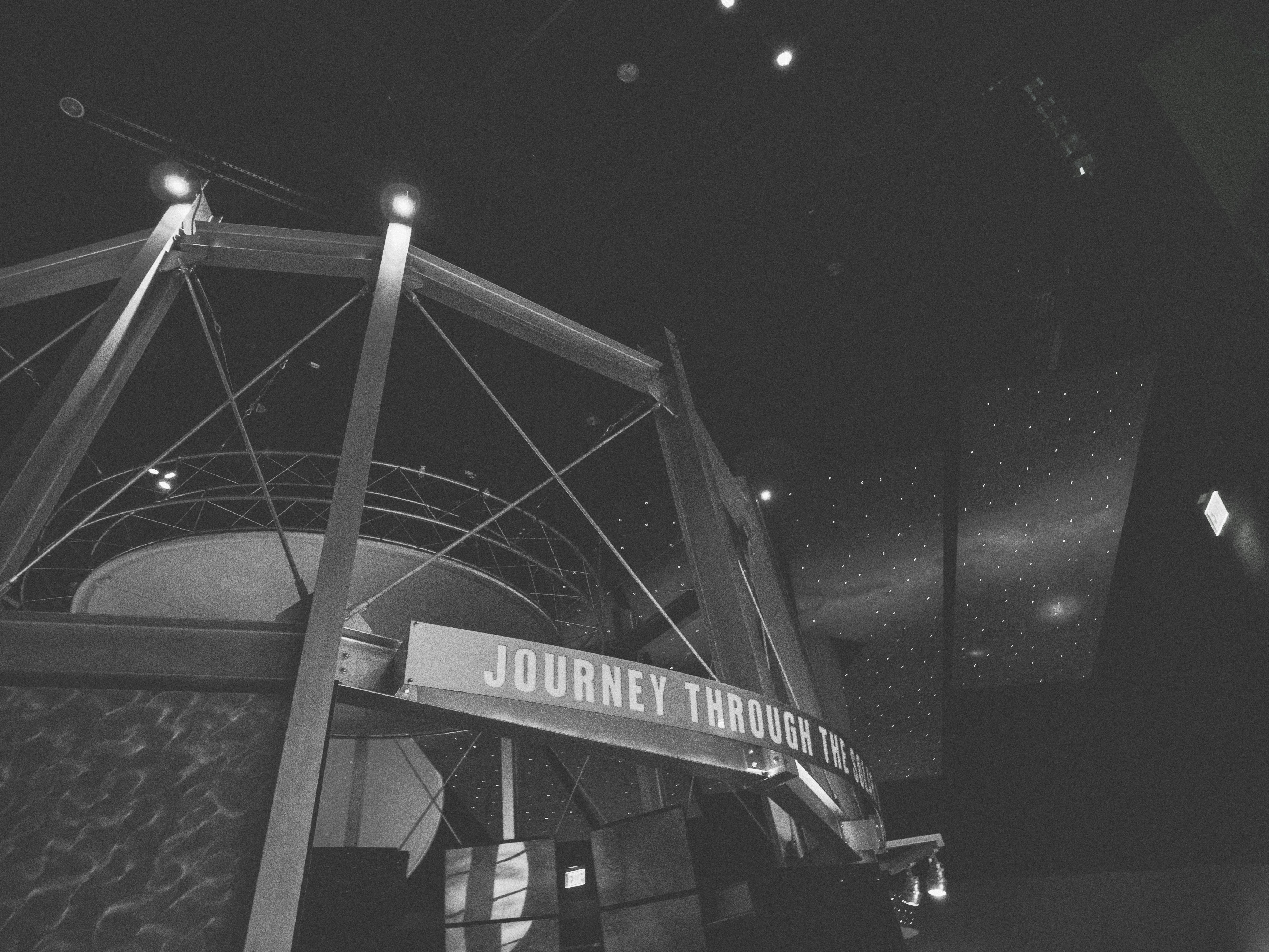 Signage reading 'JOURNEY THROUGH THE STARS' beneath a dome structure in a darkened exhibition space. The ceiling is adorned with twinkling lights resembling a night sky.