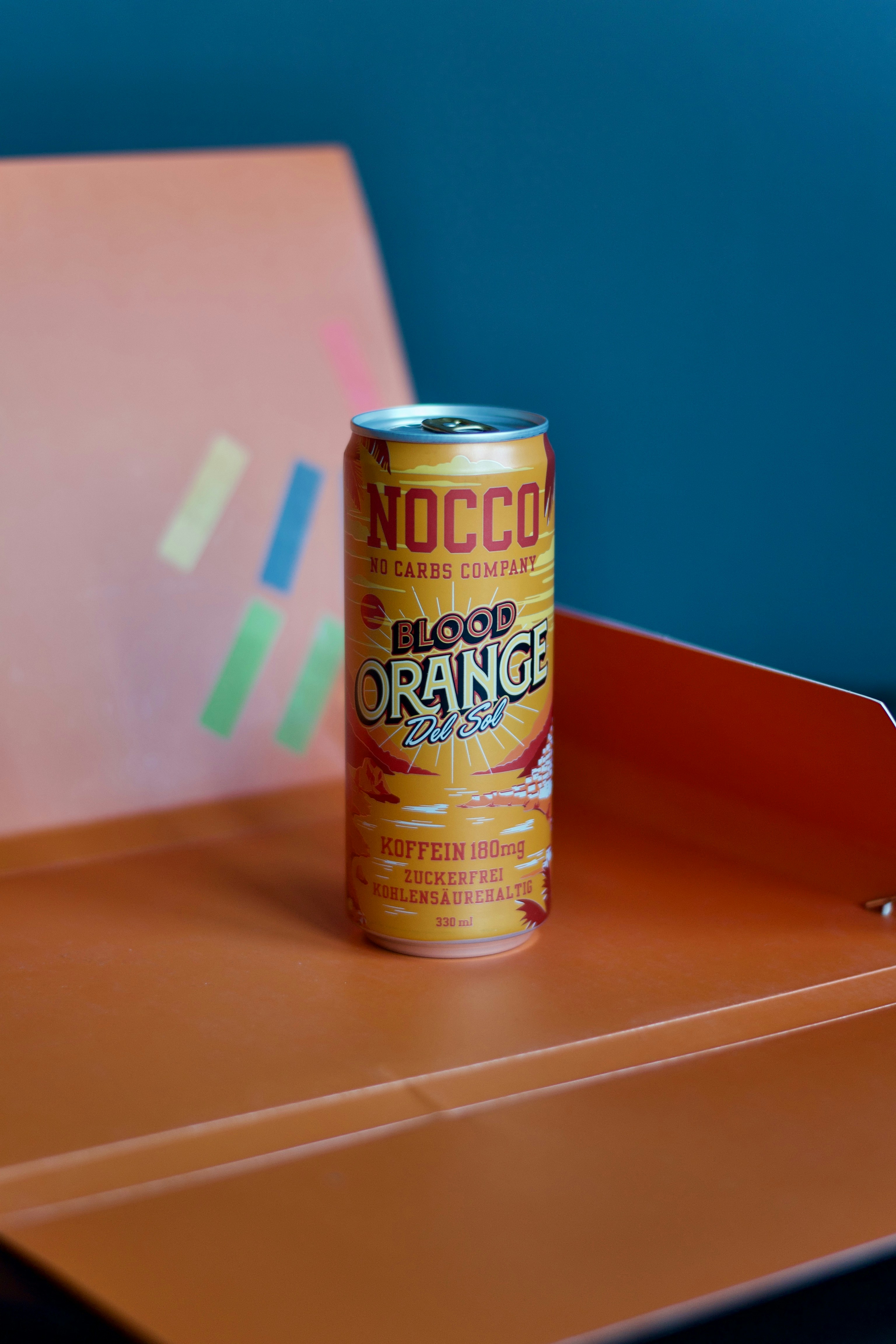 NOCCO Blood Orange on a Tangerine Stage Against a Teal Backdrop