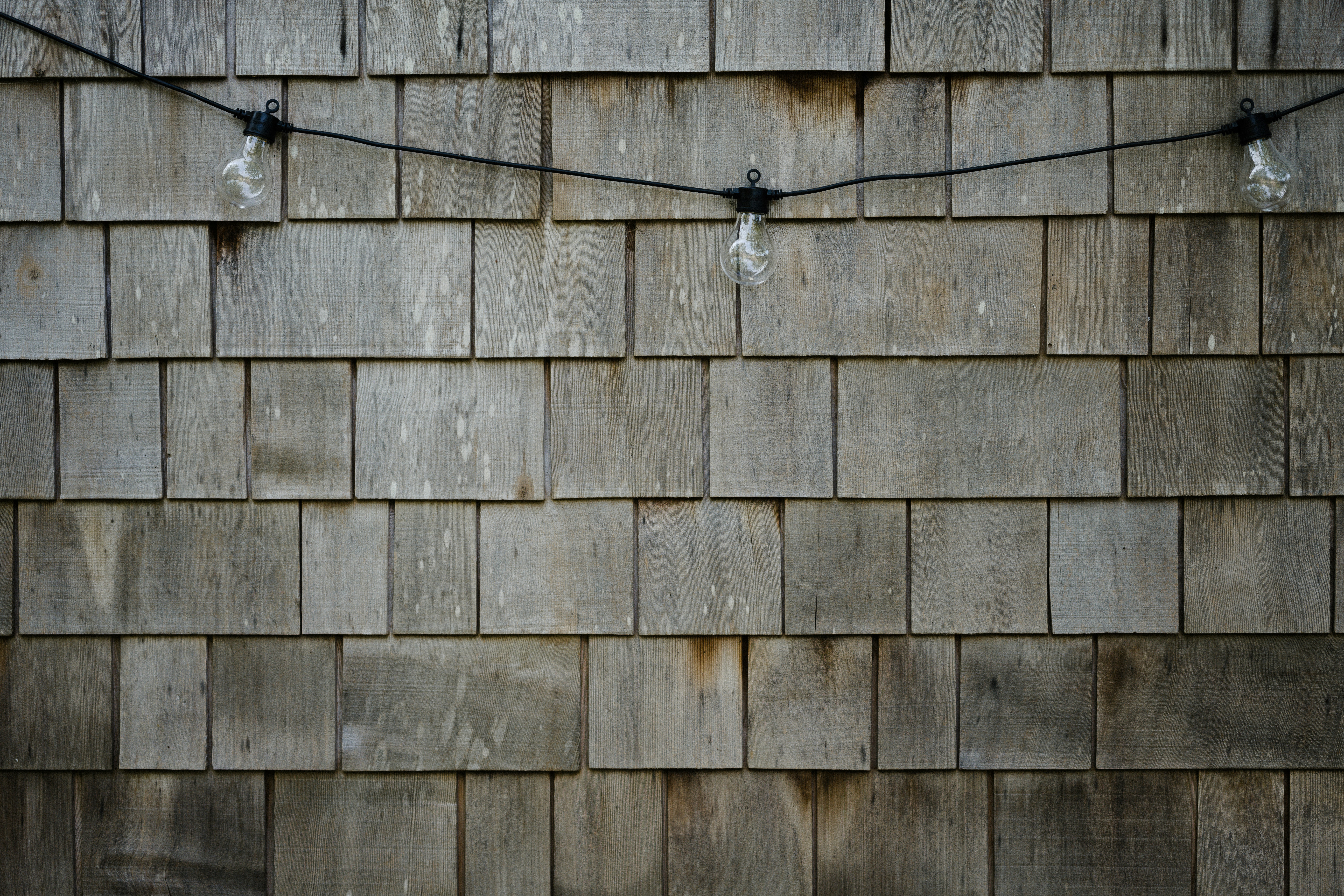 Midline Glow: A string of bulbs tracing a weathered cedar facade