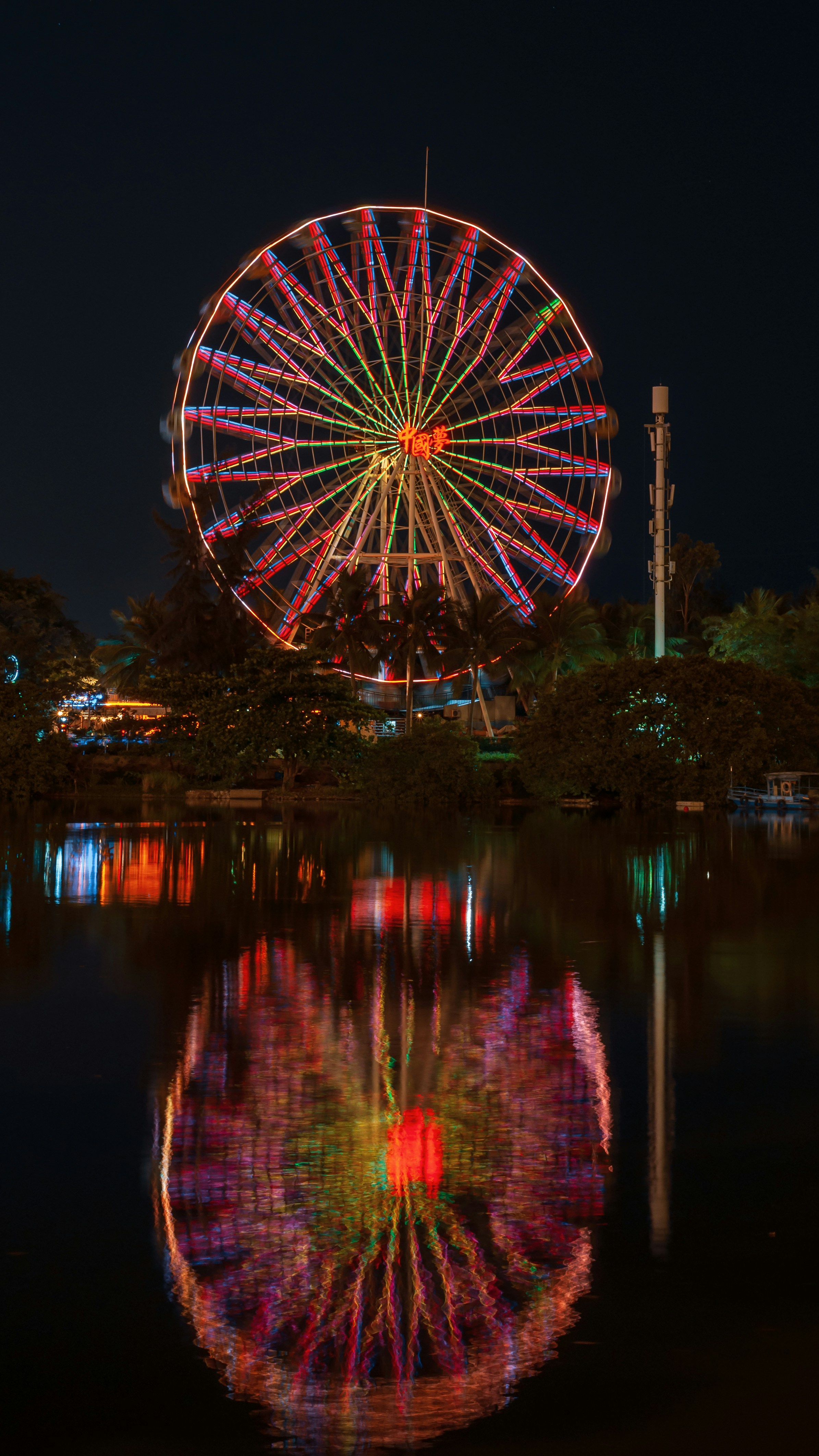 A large ferris wheel sitting above a lake at night photo – Free ...